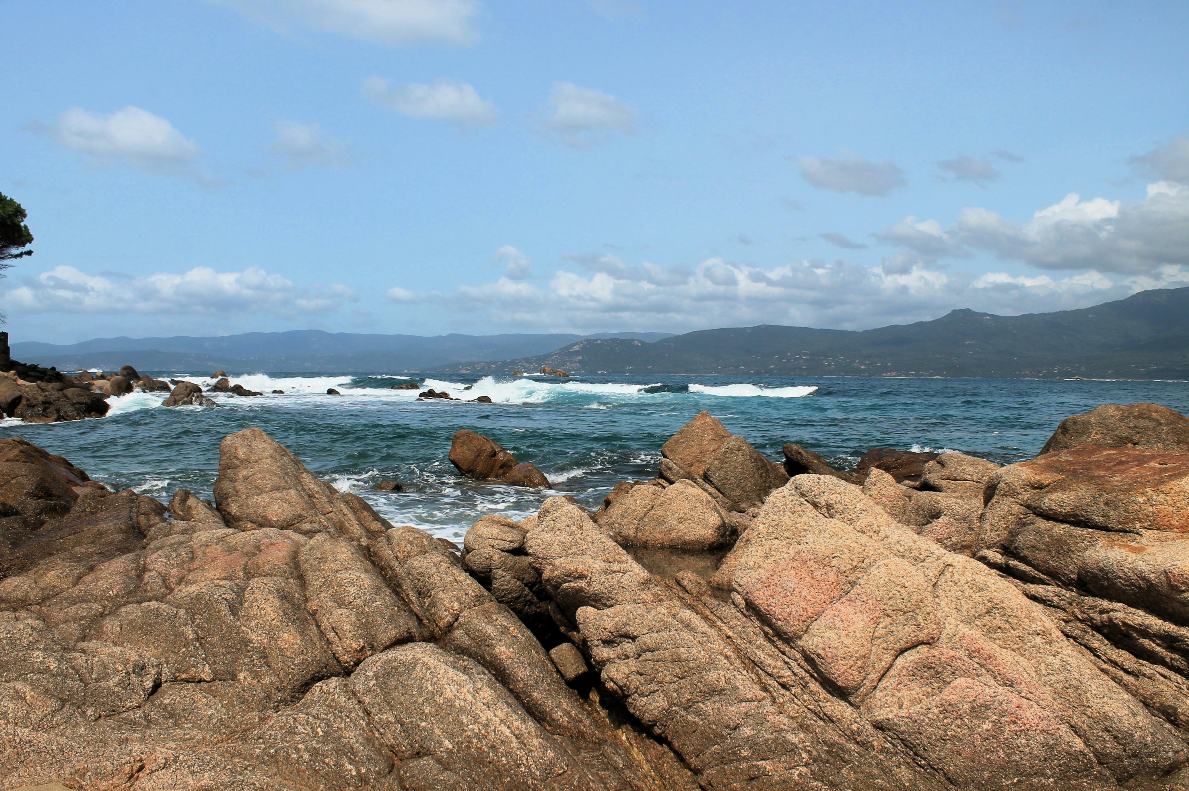 Seashore With Rocks Under Blue Sky · Free Stock Photo