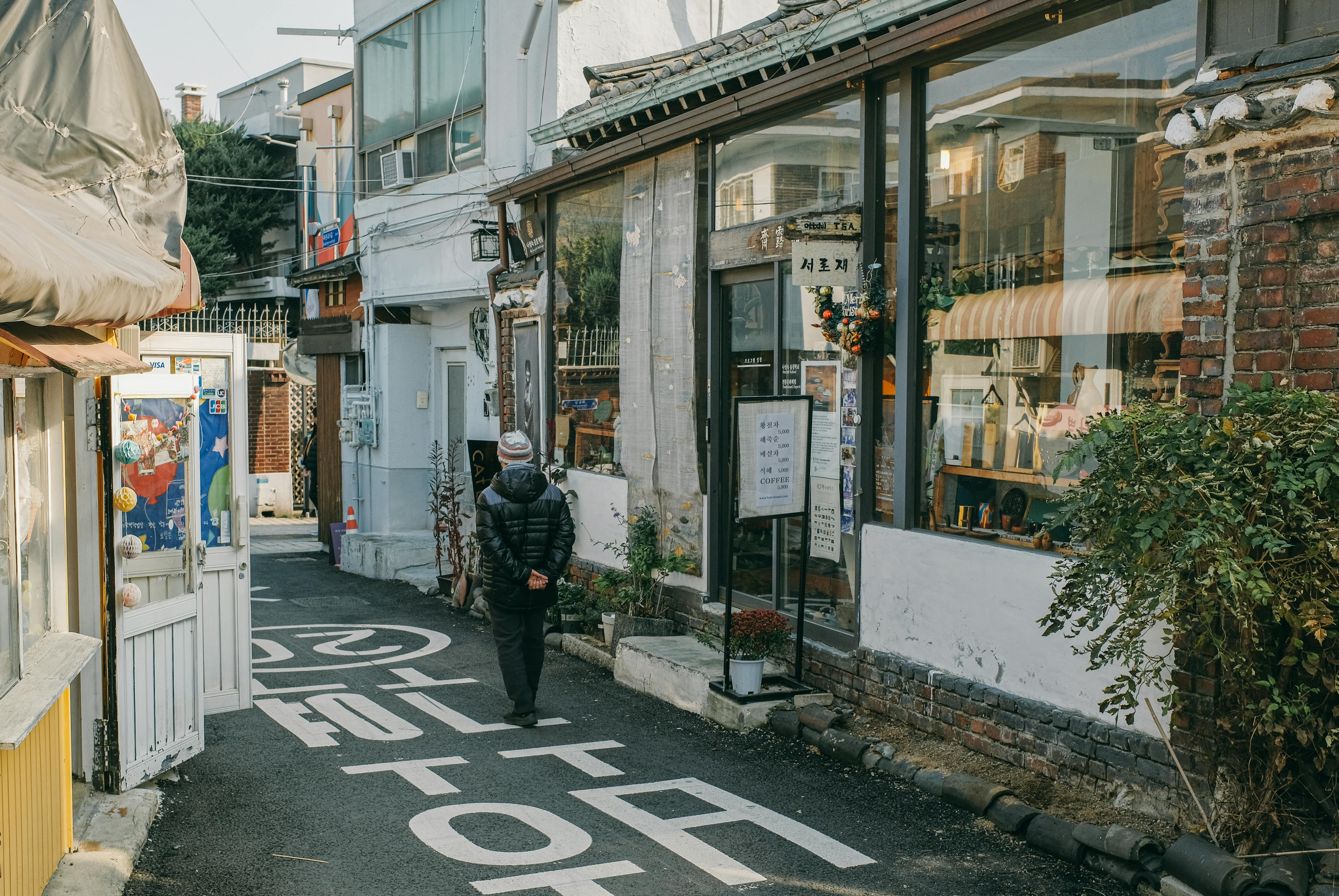 Back View of a Man Walking in the Alley between Shops in City · Free ...
