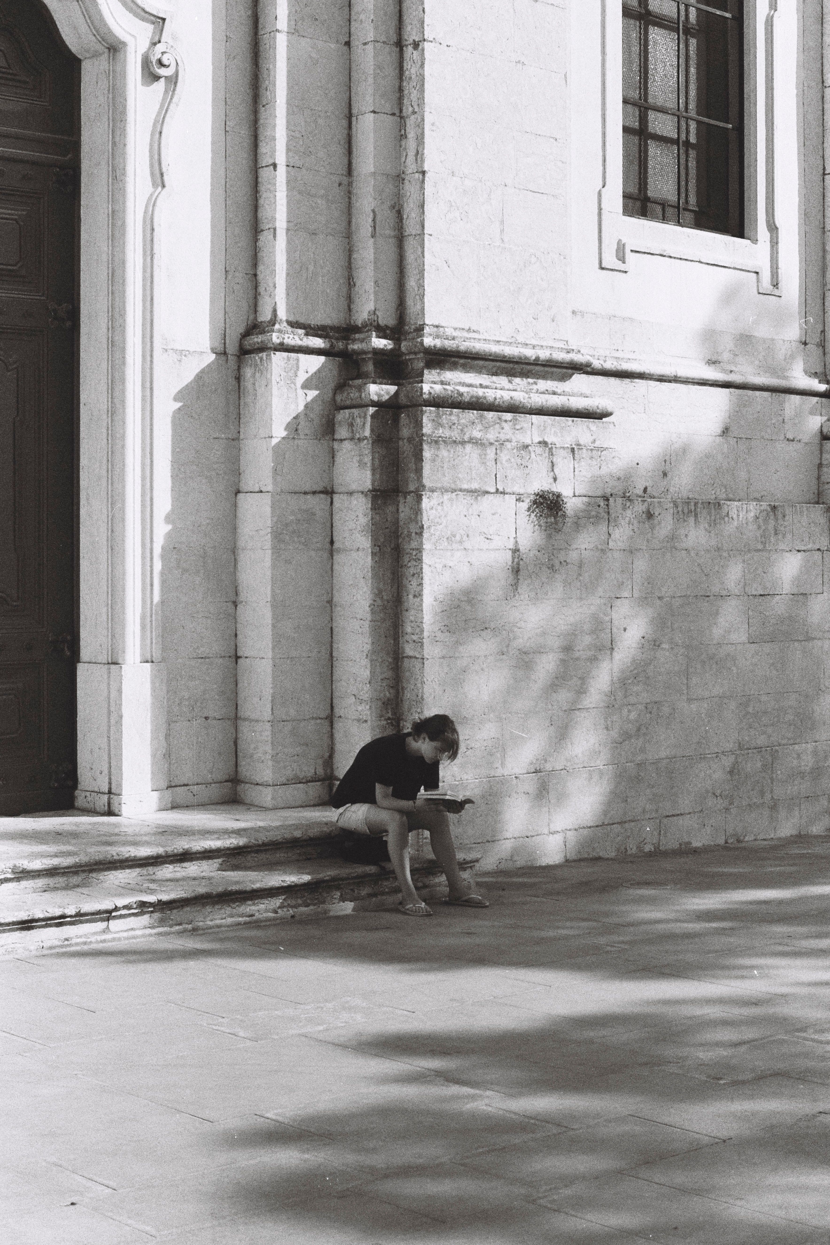 Black and White Photo of a Young Man Reading a Book under a Gate · Free ...