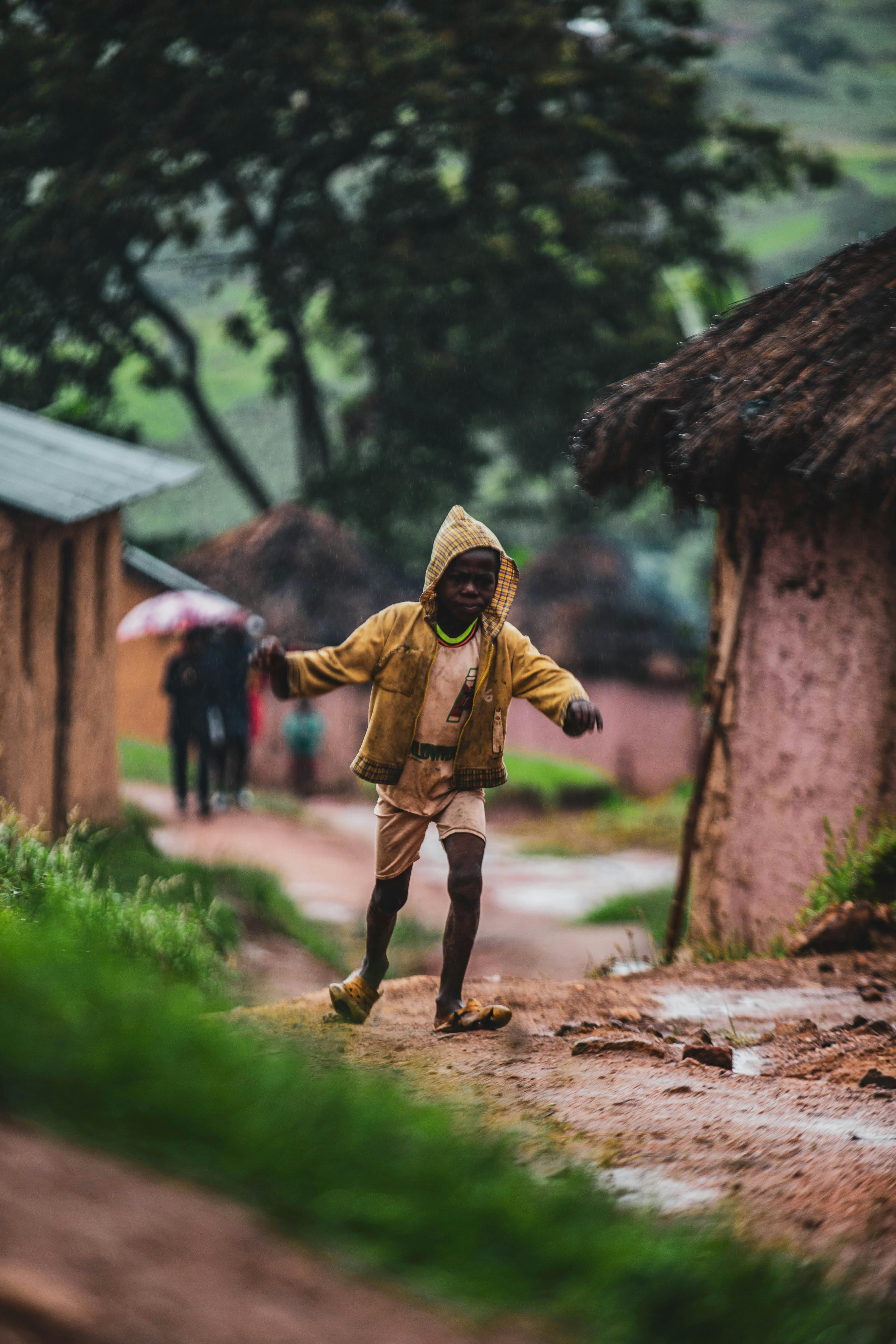 Boy in Hooded Jacket Running between Village Houses in Rain · Free ...