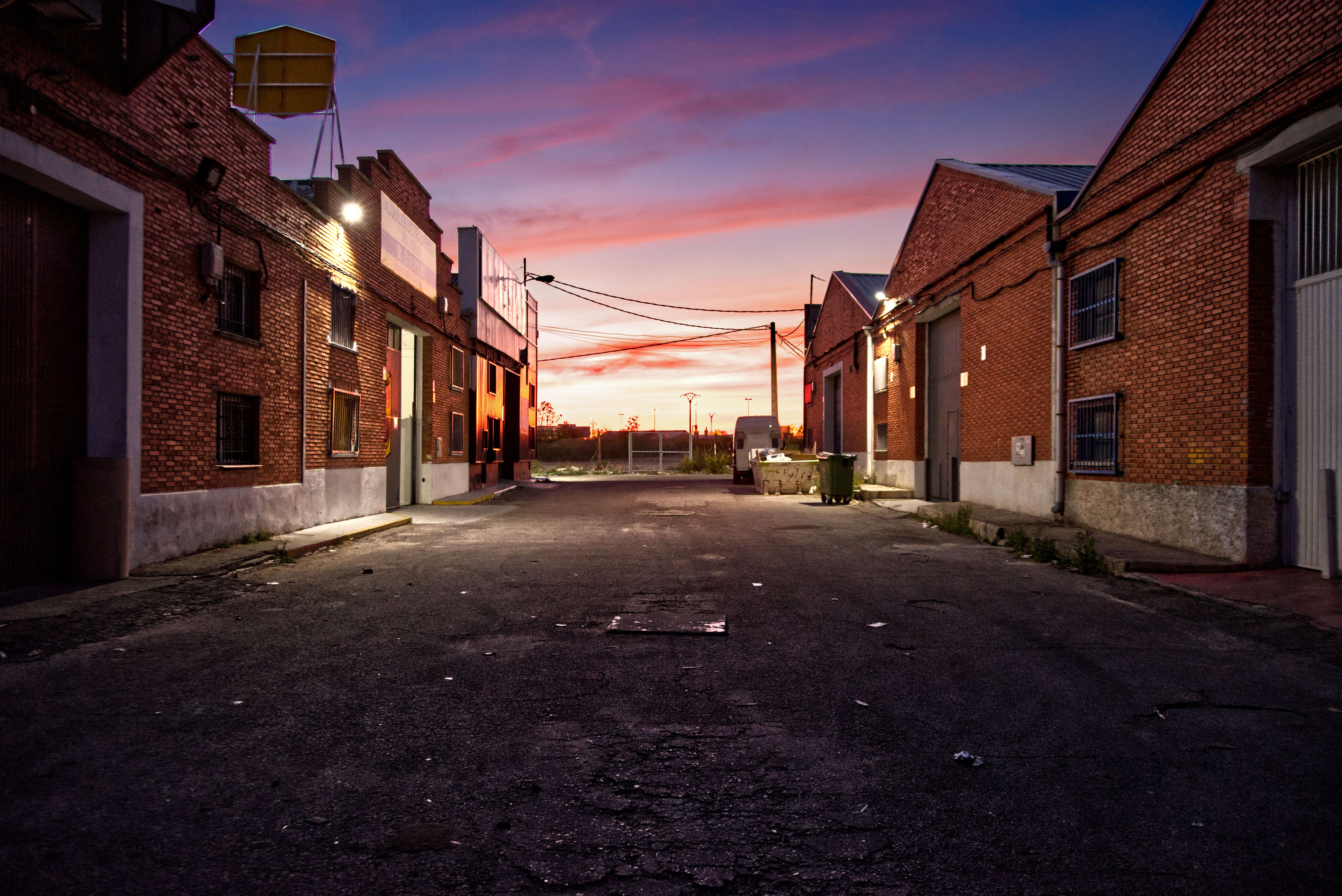 Asphalt Road between Buildings at Sunset · Free Stock Photo