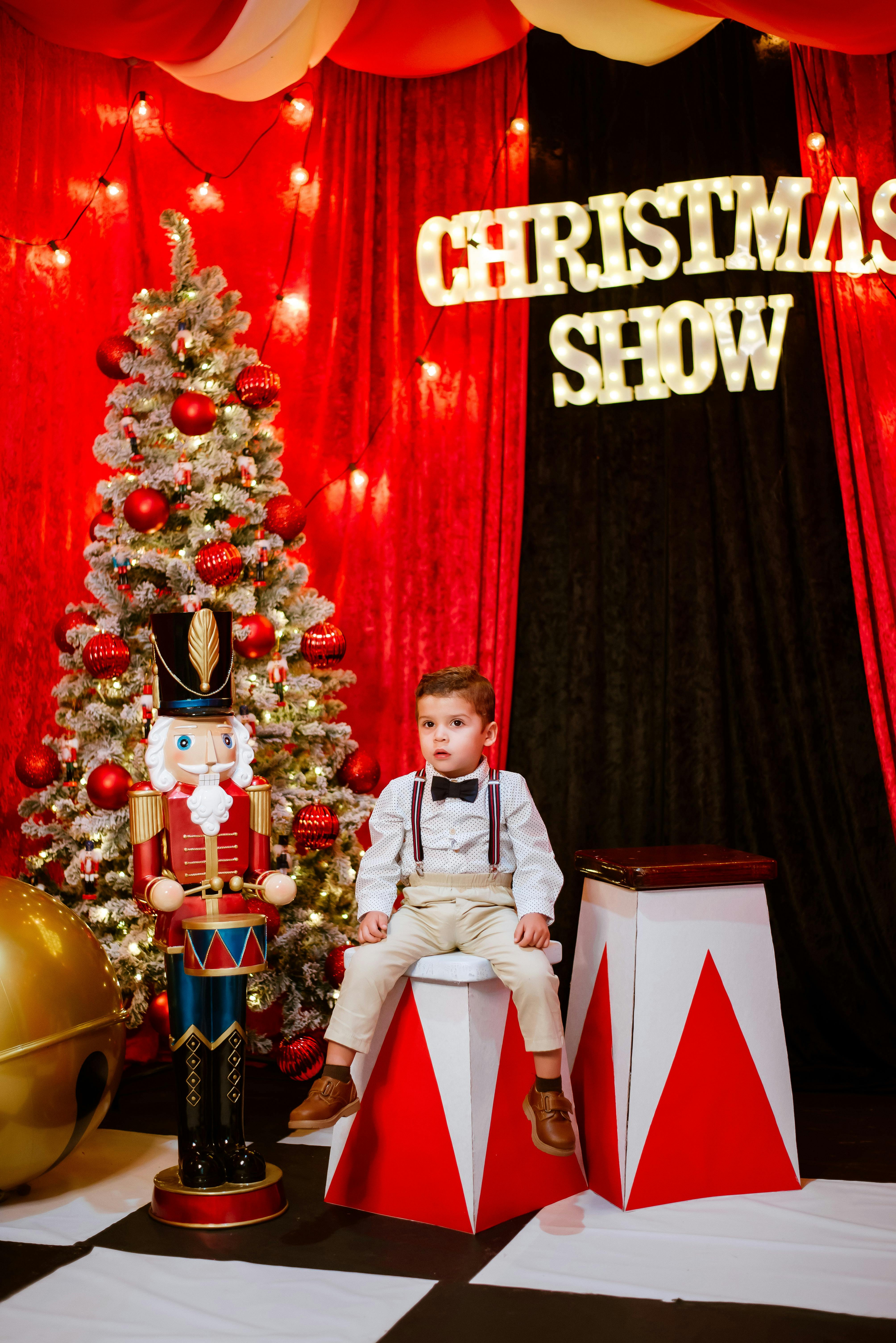 Little Boy Sitting on a Trapeze Next to a Nutcracker Statue and ...