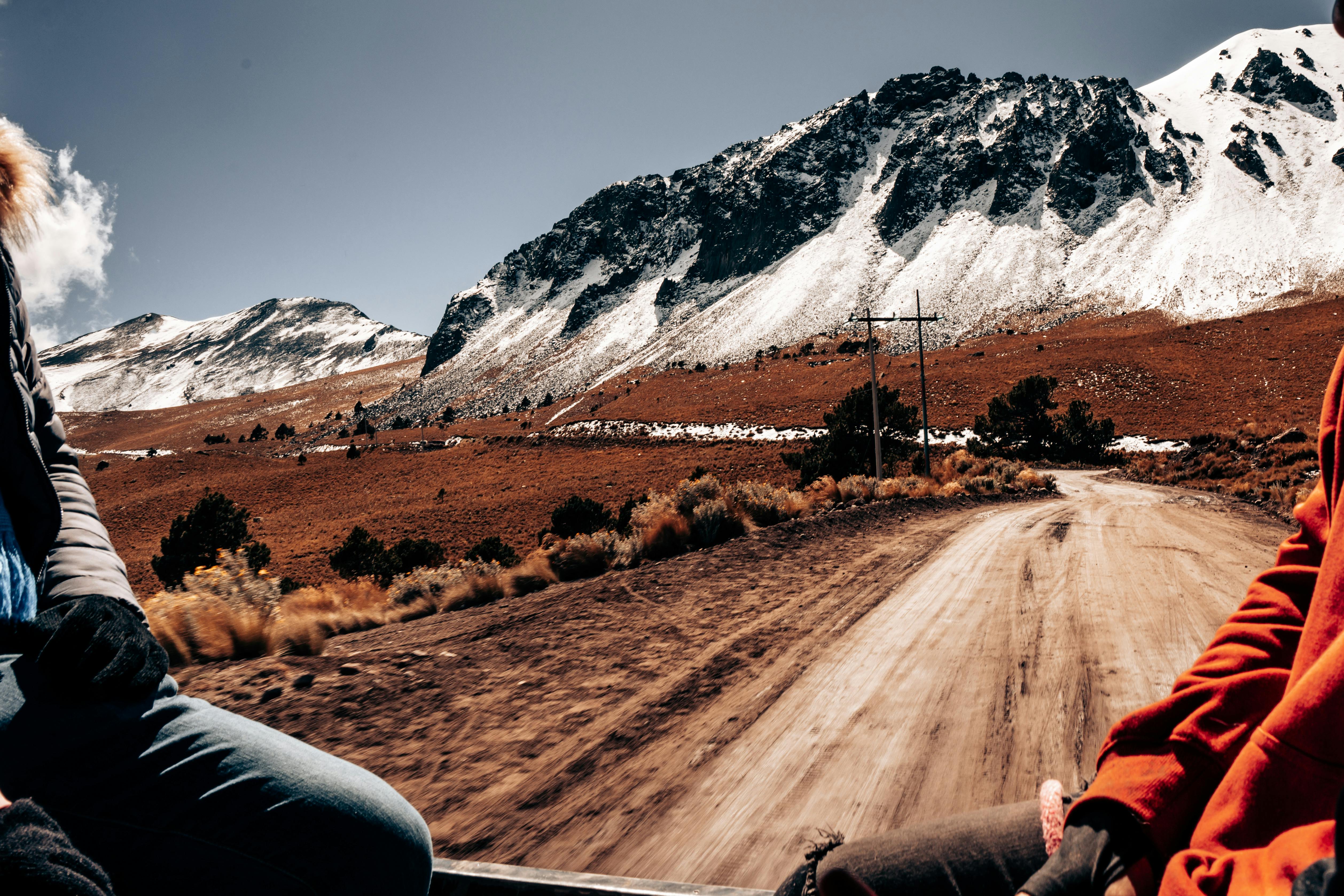 Dirt Road and Mountains behind People Riding in Trunk of Pick-up · Free ...