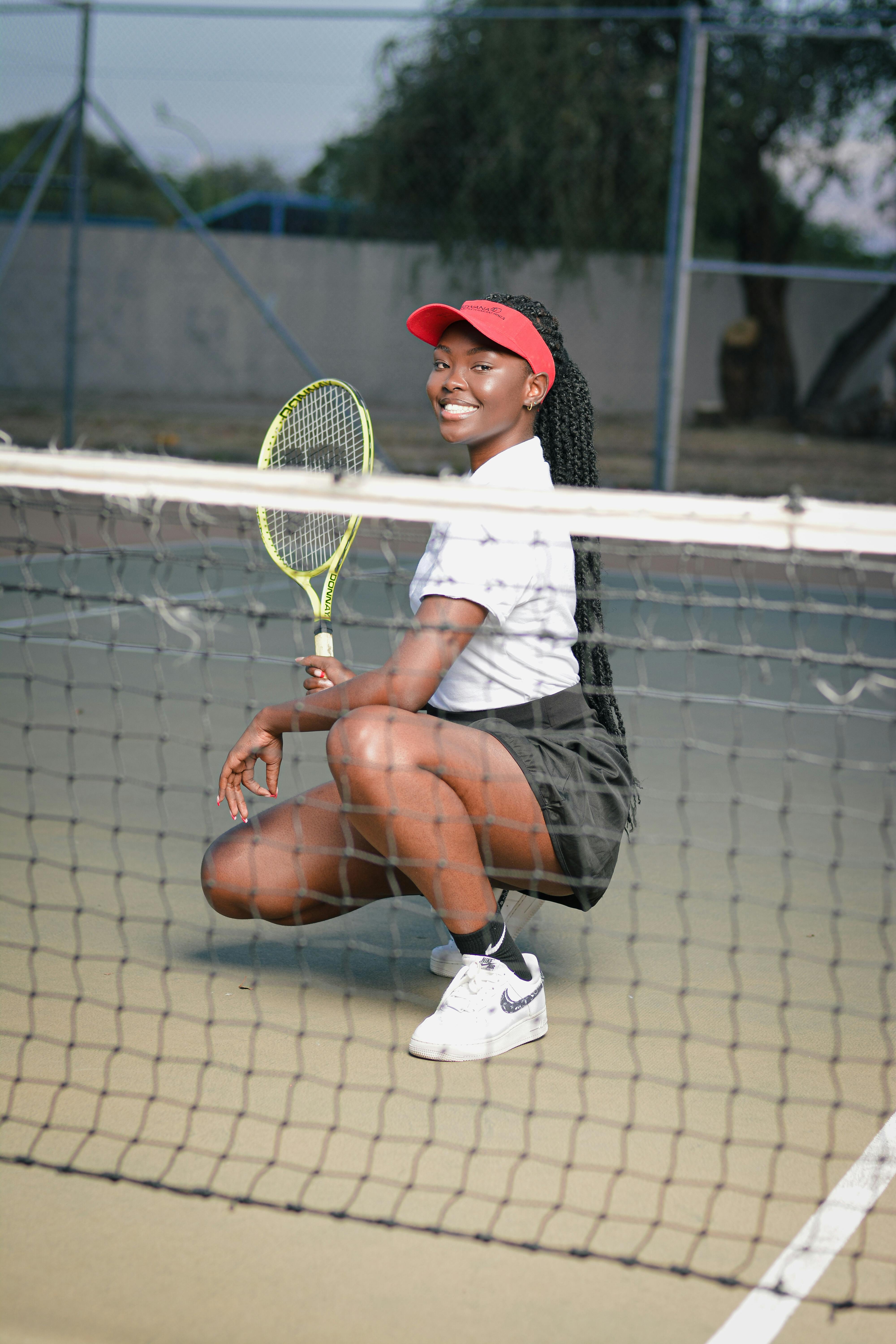 Smiling Woman Crouching behind Tennis Net · Free Stock Photo