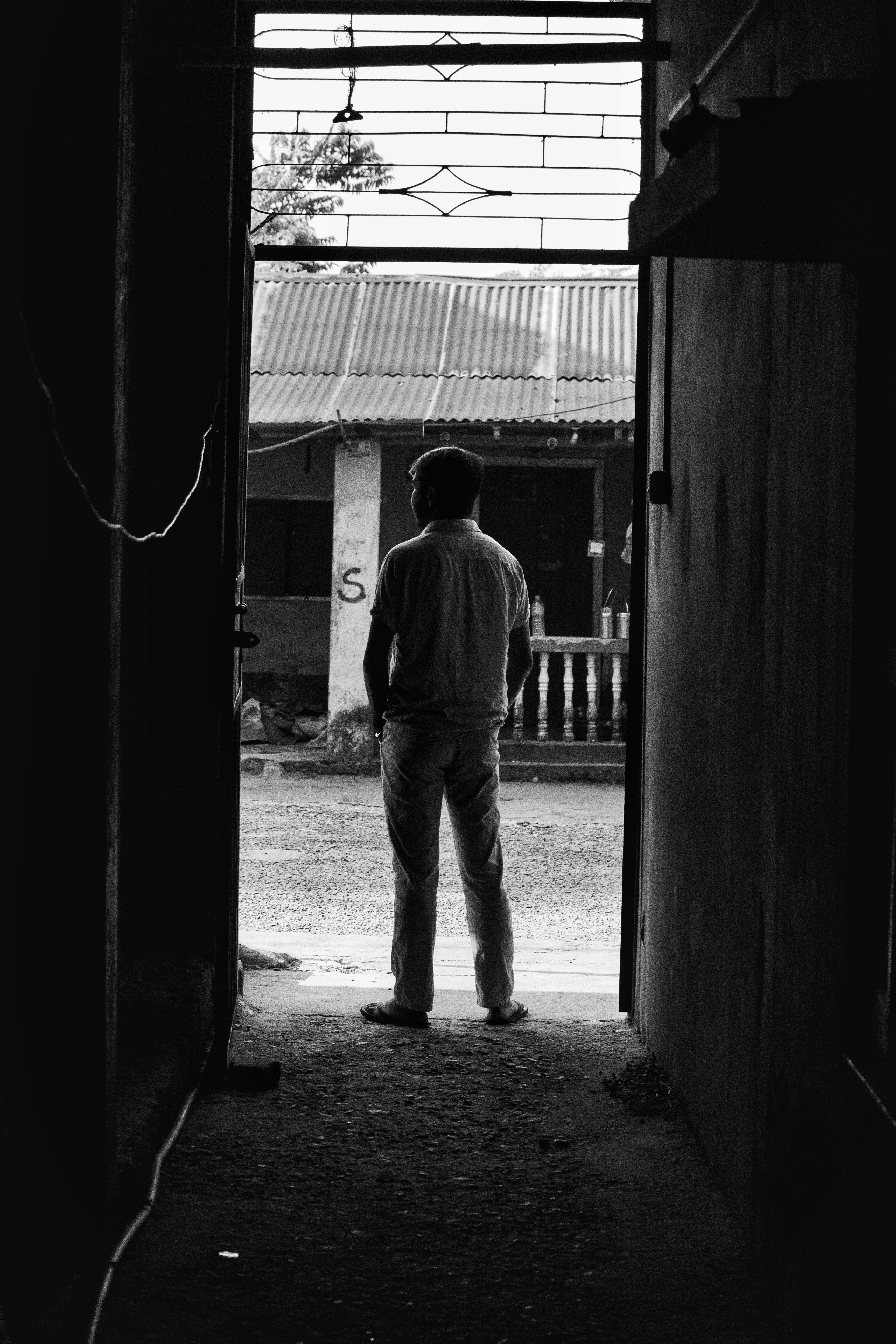 Man Standing in an Alley in Black and White · Free Stock Photo