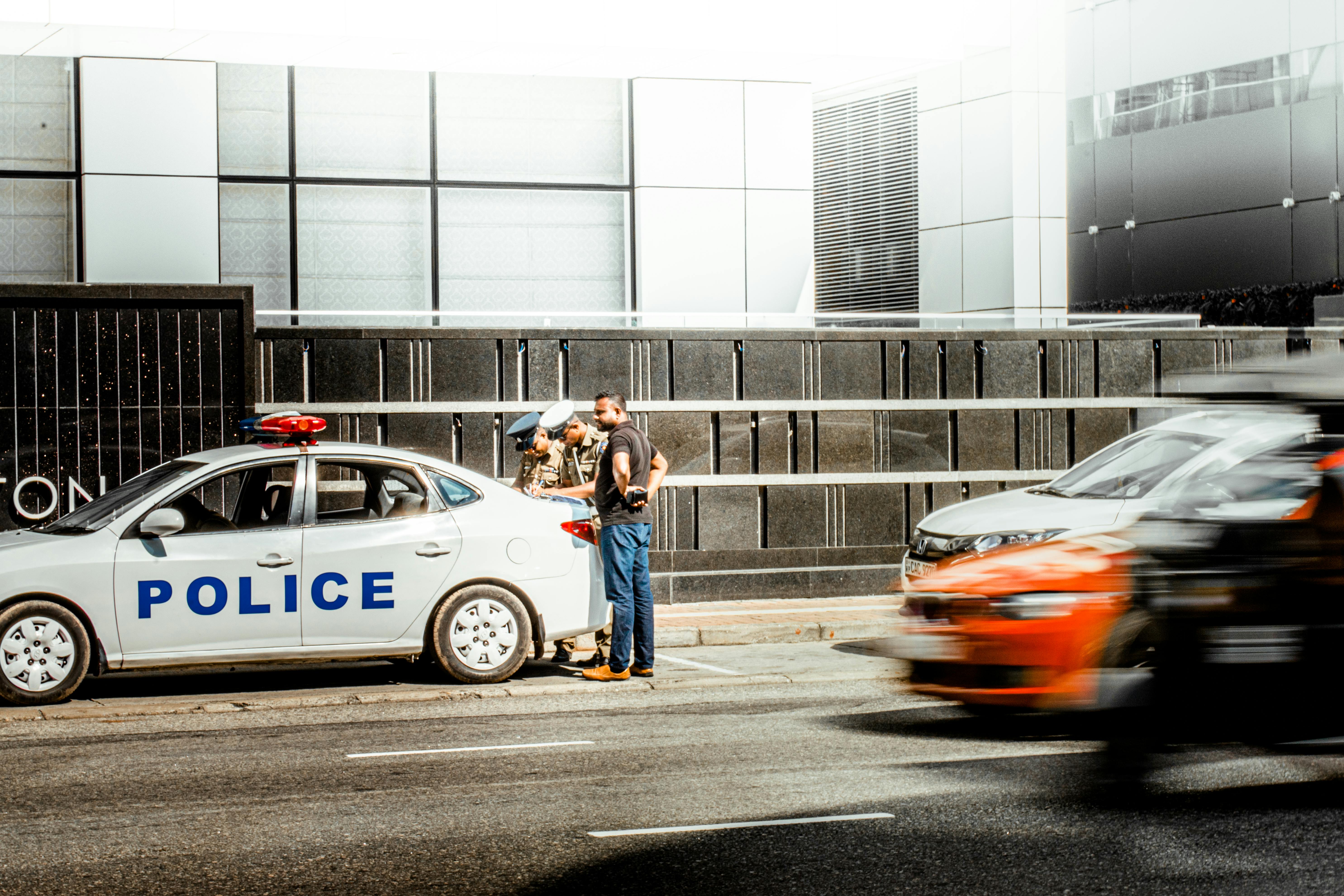 Driver Standing with Police Officers by Police Car · Free Stock Photo
