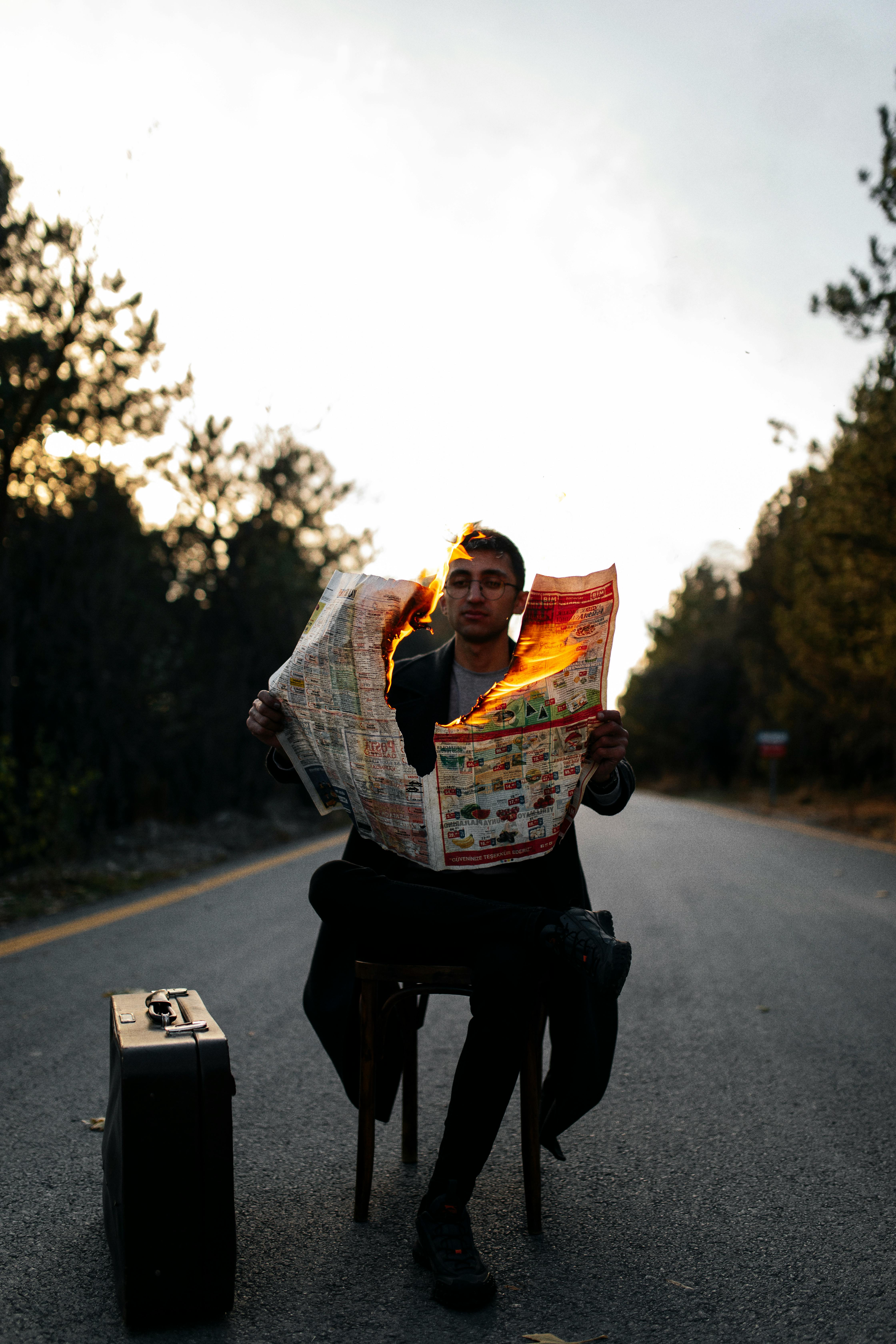 Man Sitting in the Middle of a Road and Holding a Burning Newspaper ...