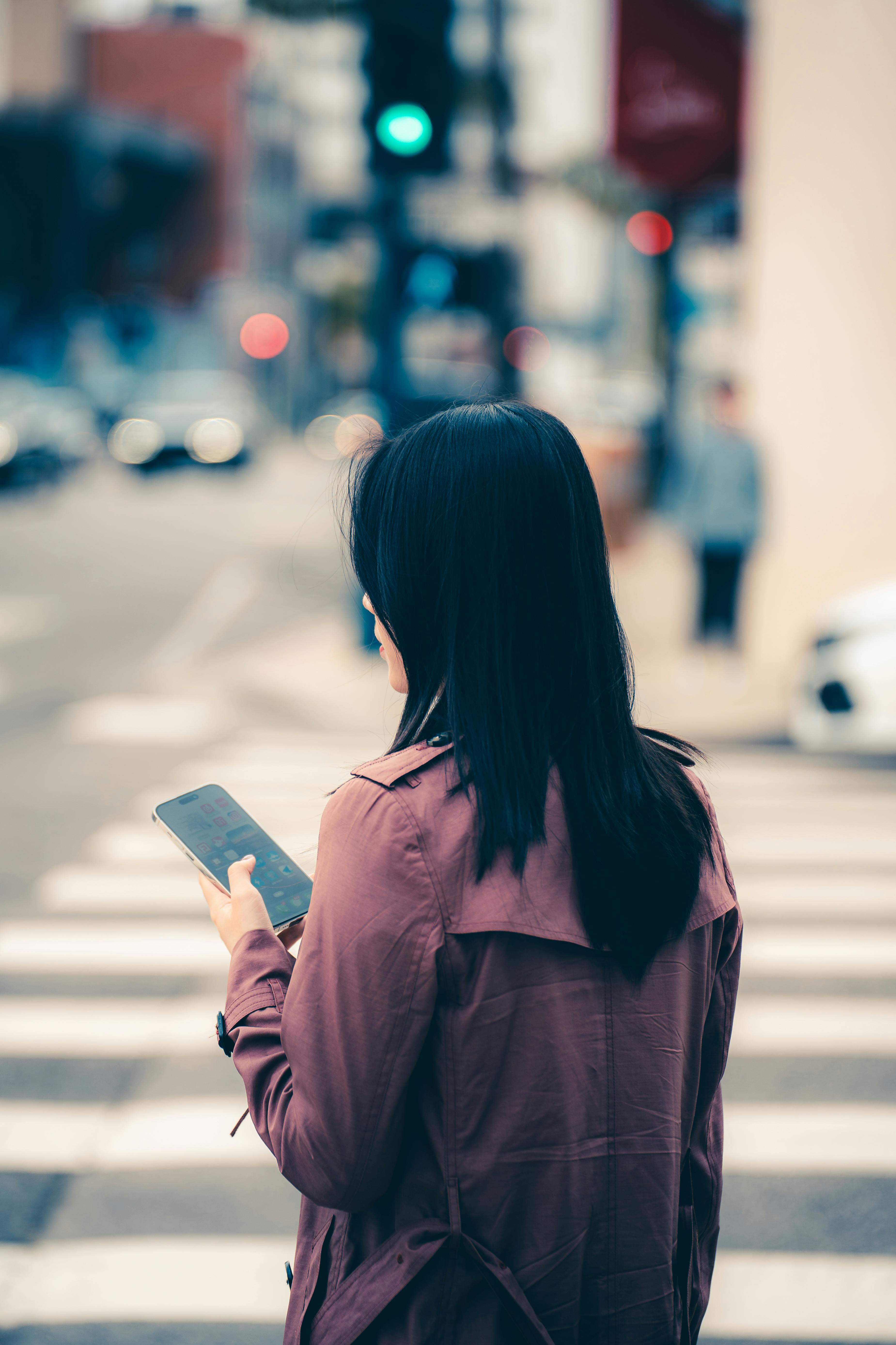 Back View of a Woman with a Smartphone Standing at a Crosswalk in City ...