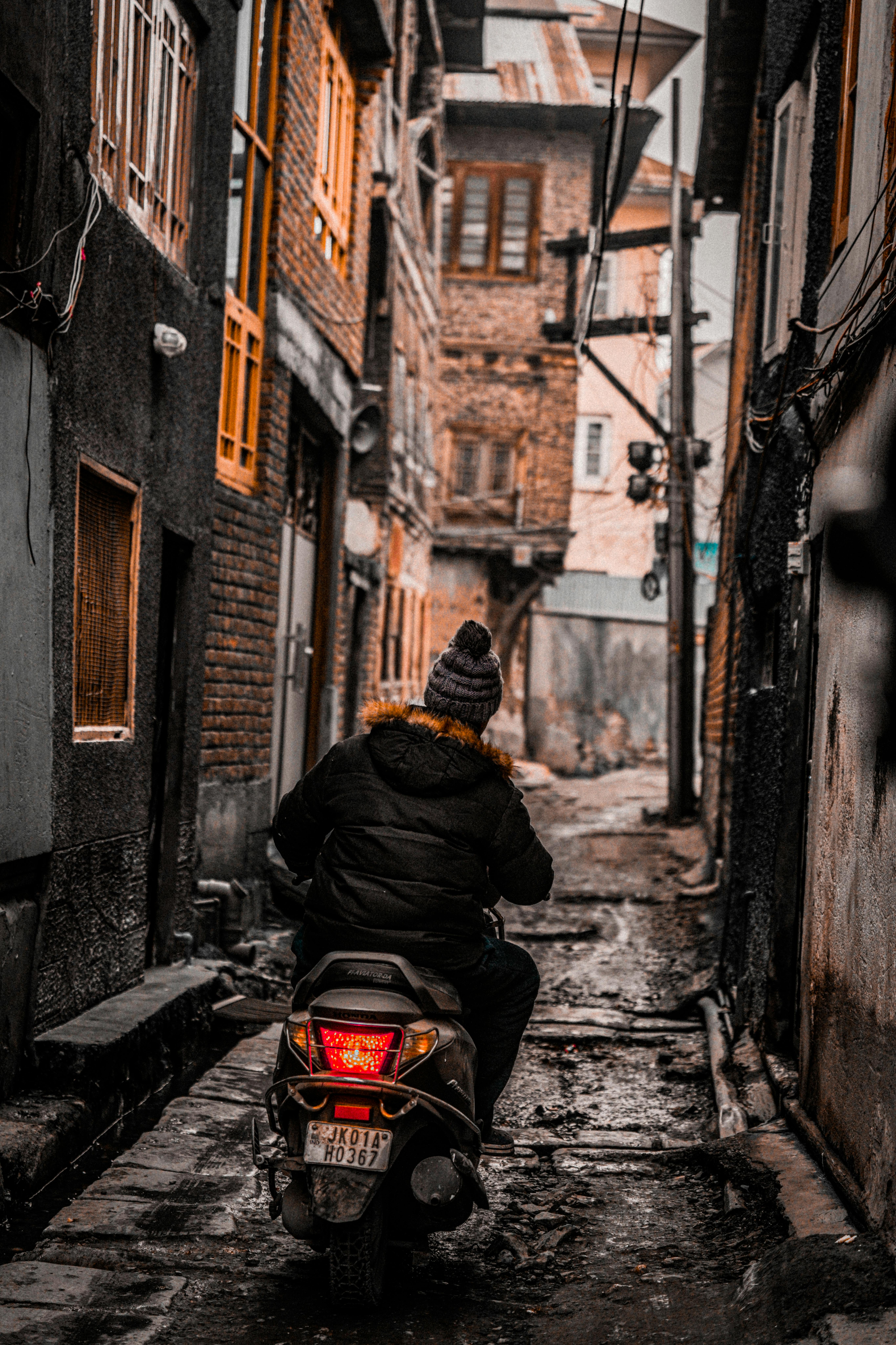 Riding a Scooter Through a Muddy Narrow Alley · Free Stock Photo