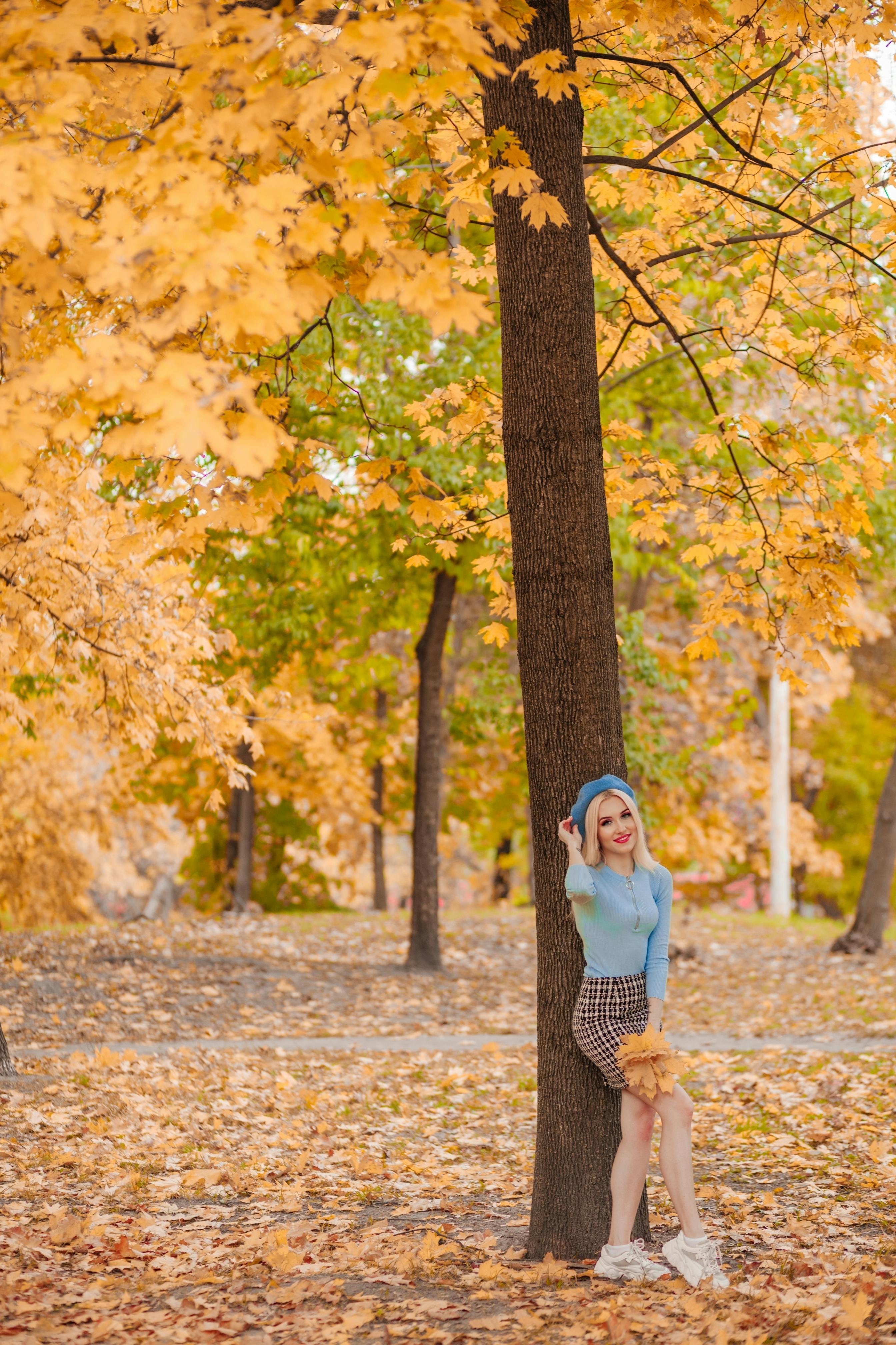 A woman standing next to a tree in the fall · Free Stock Photo