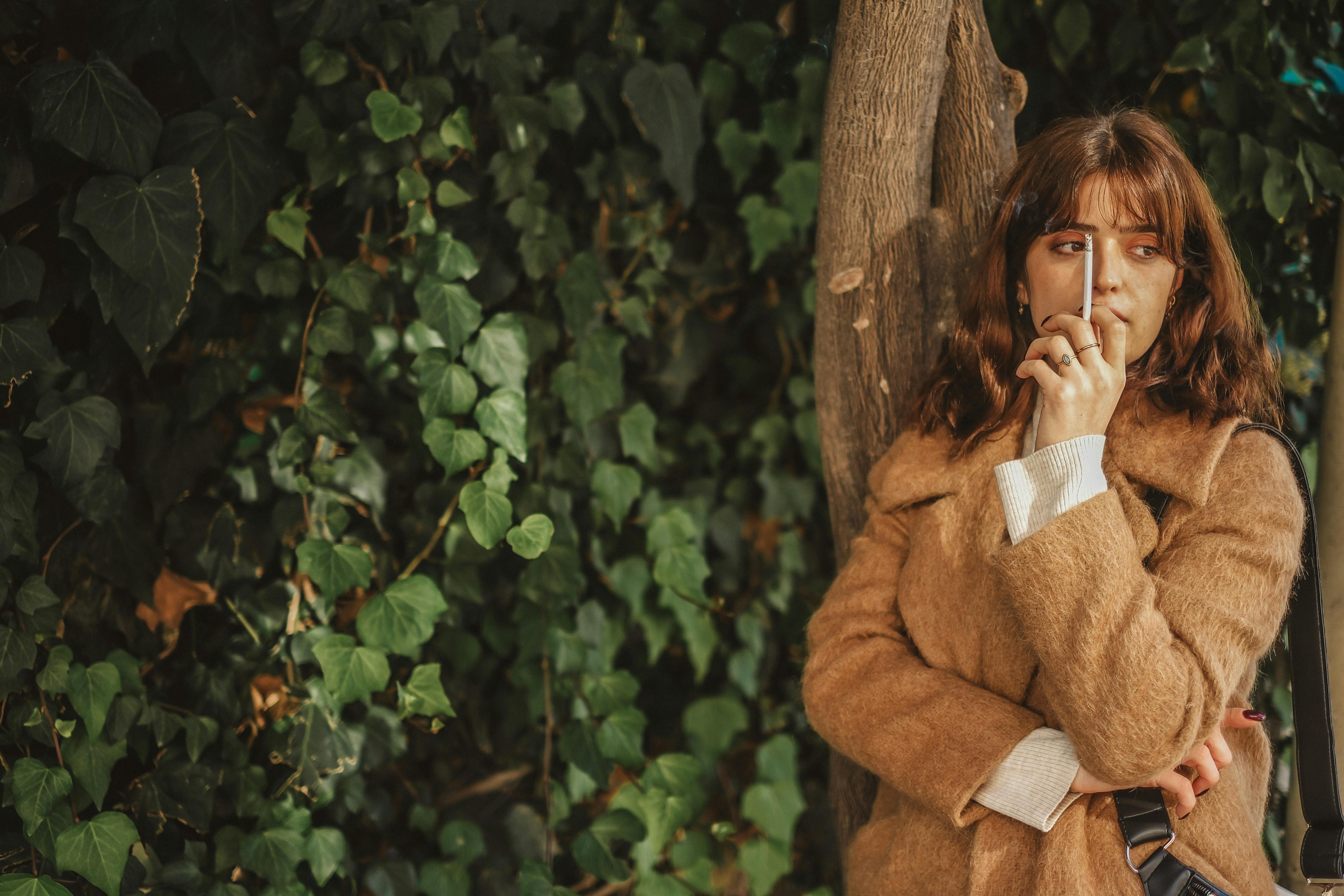 Woman Standing by the Tree and Smoking a Cigarette · Free Stock Photo