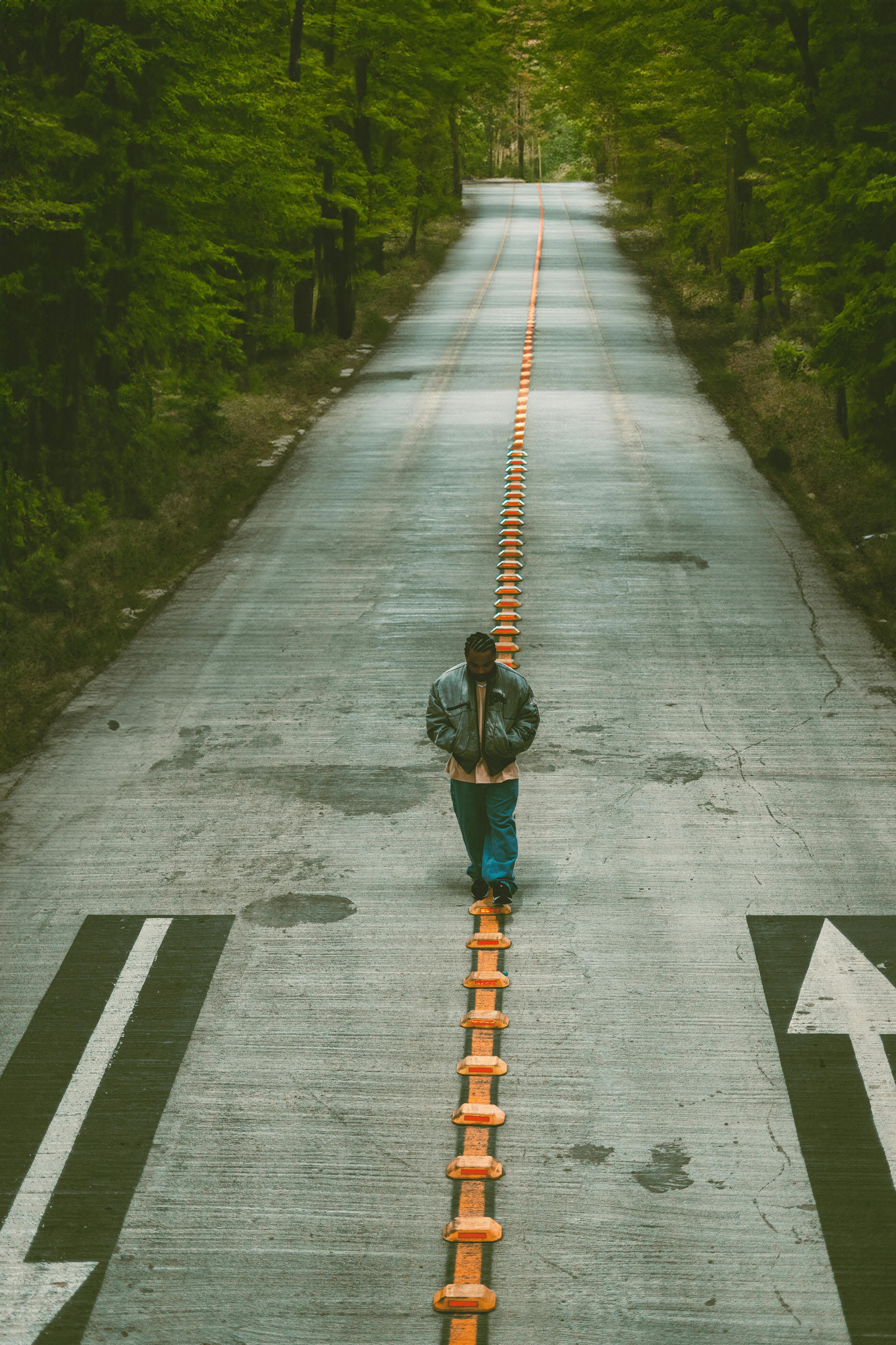 High Angle Shot of a Man Standing on an Asphalt Road · Free Stock Photo