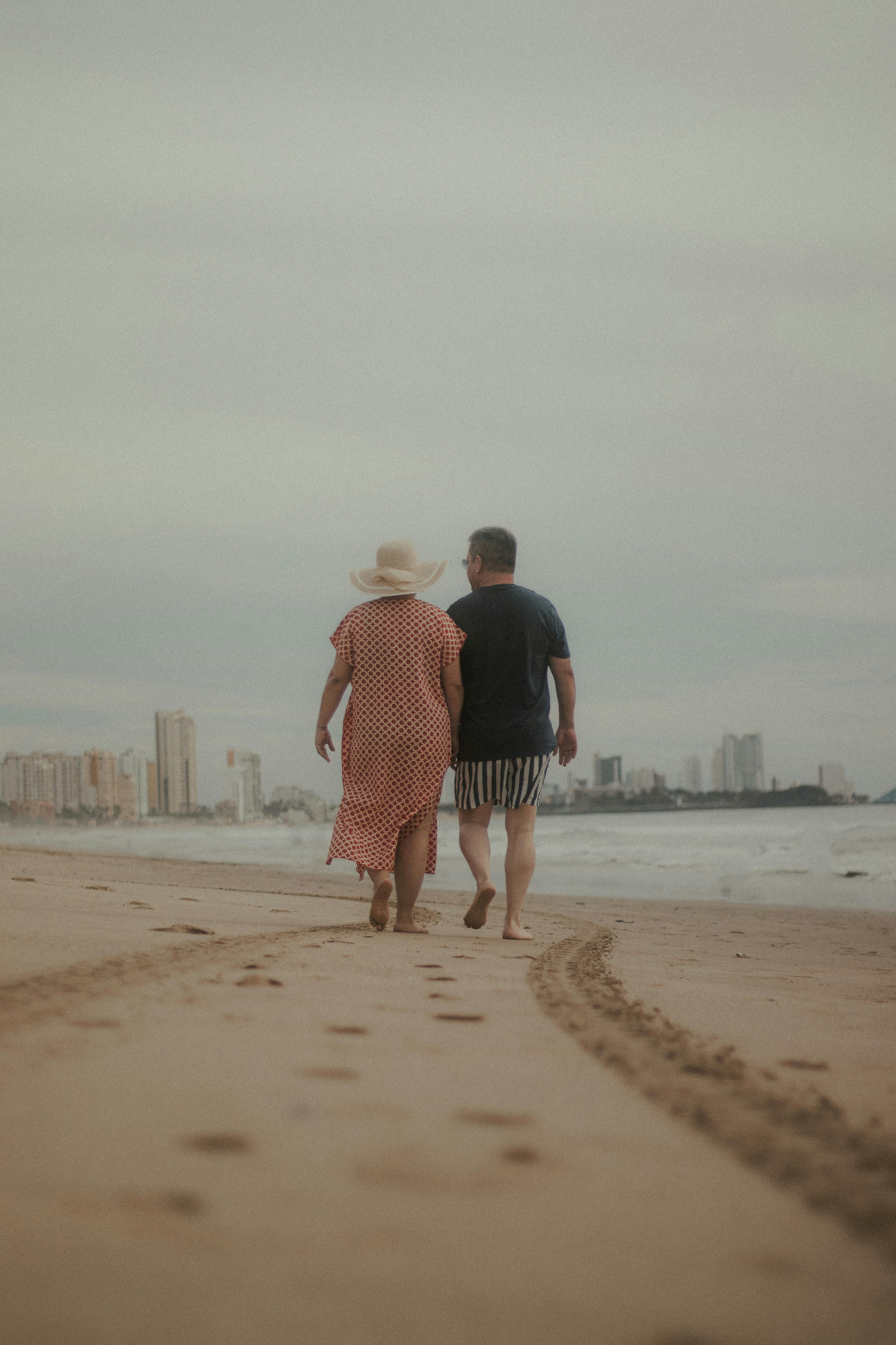 Man and Woman on Stroll along Sandy Beach · Free Stock Photo