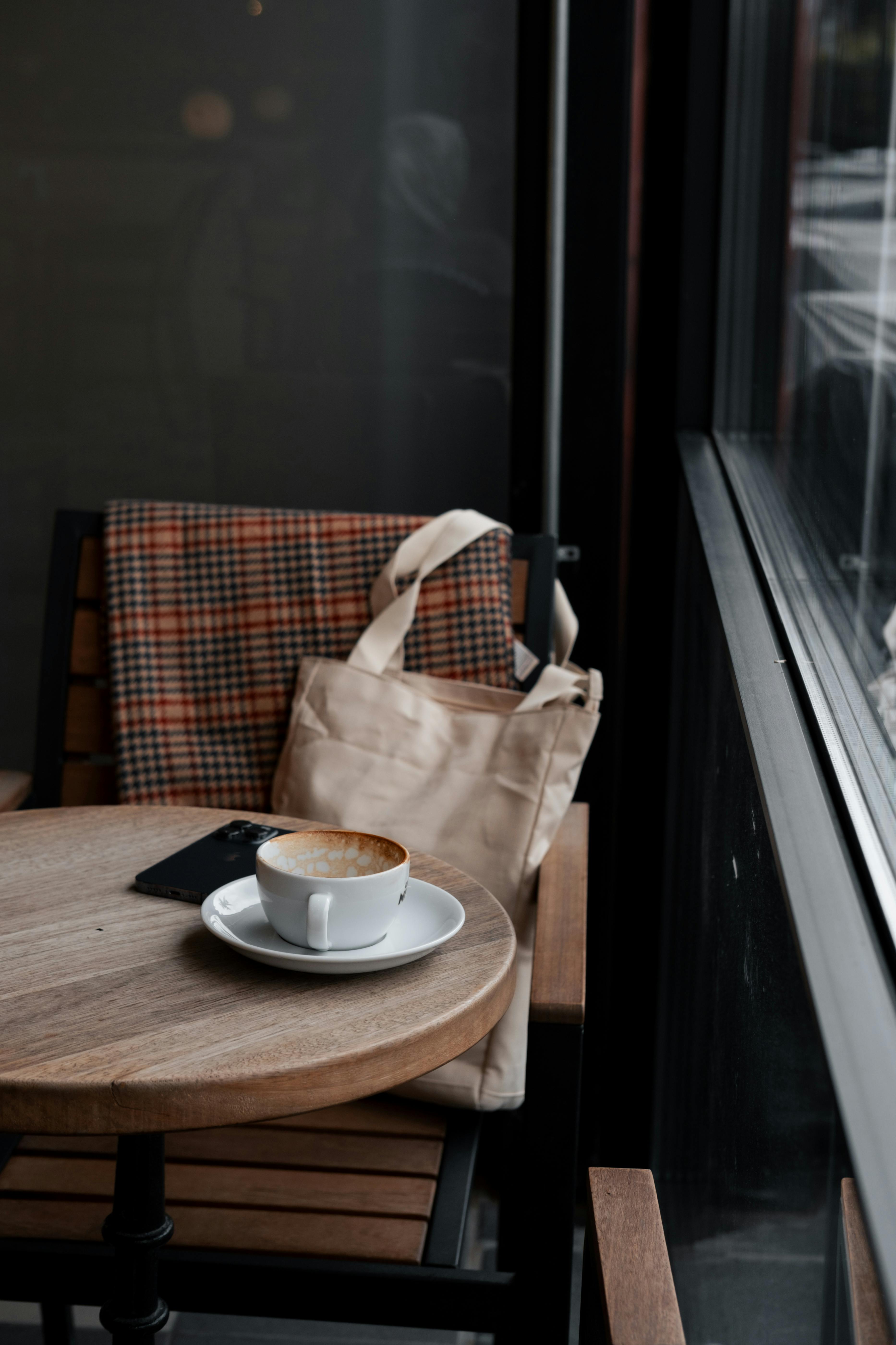 Coffee on a Table in a Cafe and a Tote Bag on a Chair · Free Stock Photo