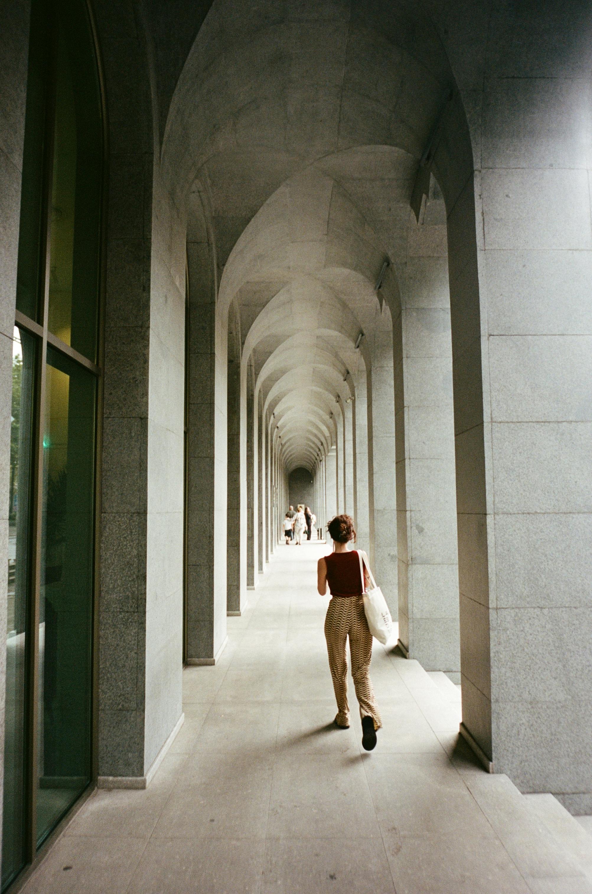 Woman Walking in an Arcade · Free Stock Photo