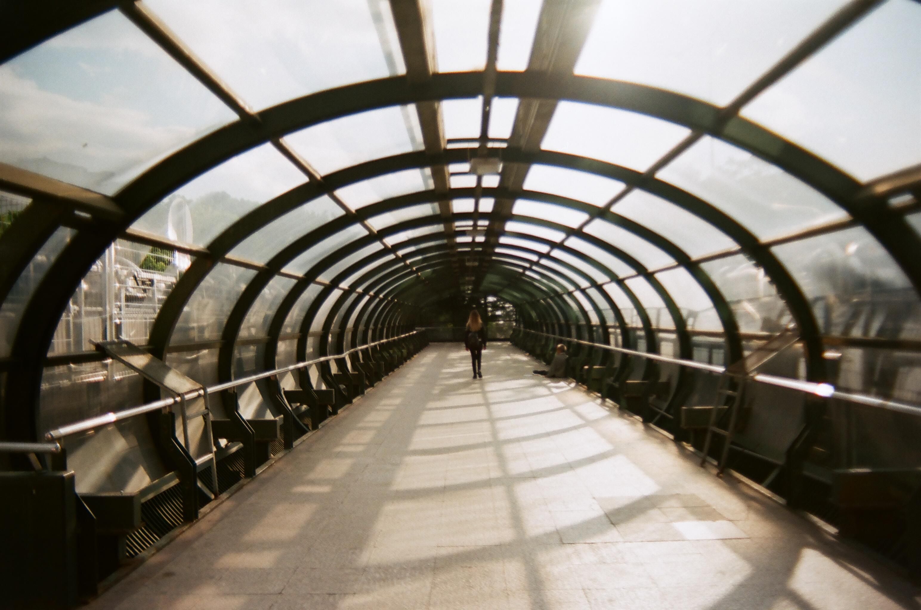 Back View of a Pedestrian Walking in a Modern Tunnel · Free Stock Photo