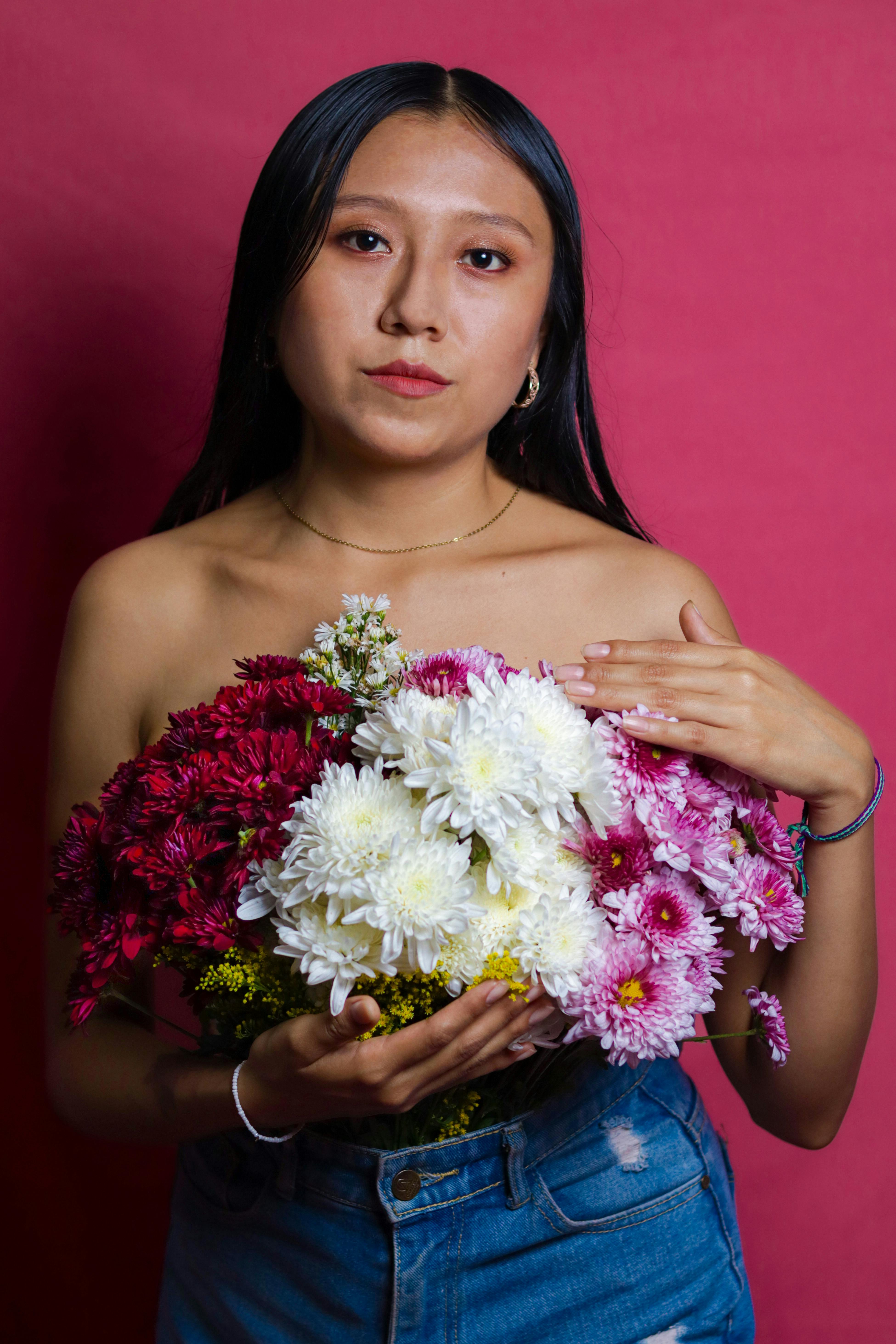Woman Sitting in Open Field with Bouquet of Red Flowers · Free Stock Photo