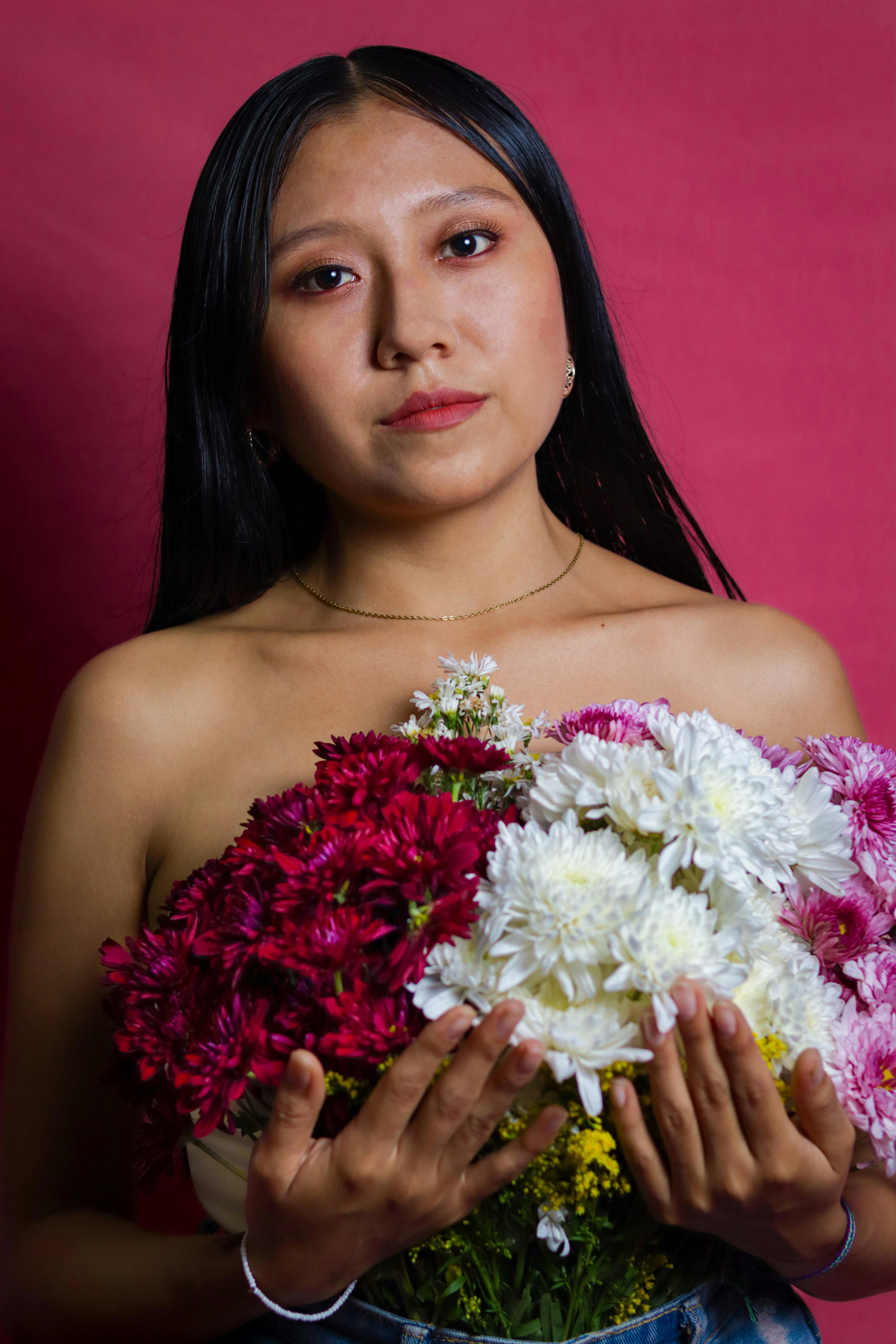Woman Sitting in Open Field with Bouquet of Red Flowers · Free Stock Photo