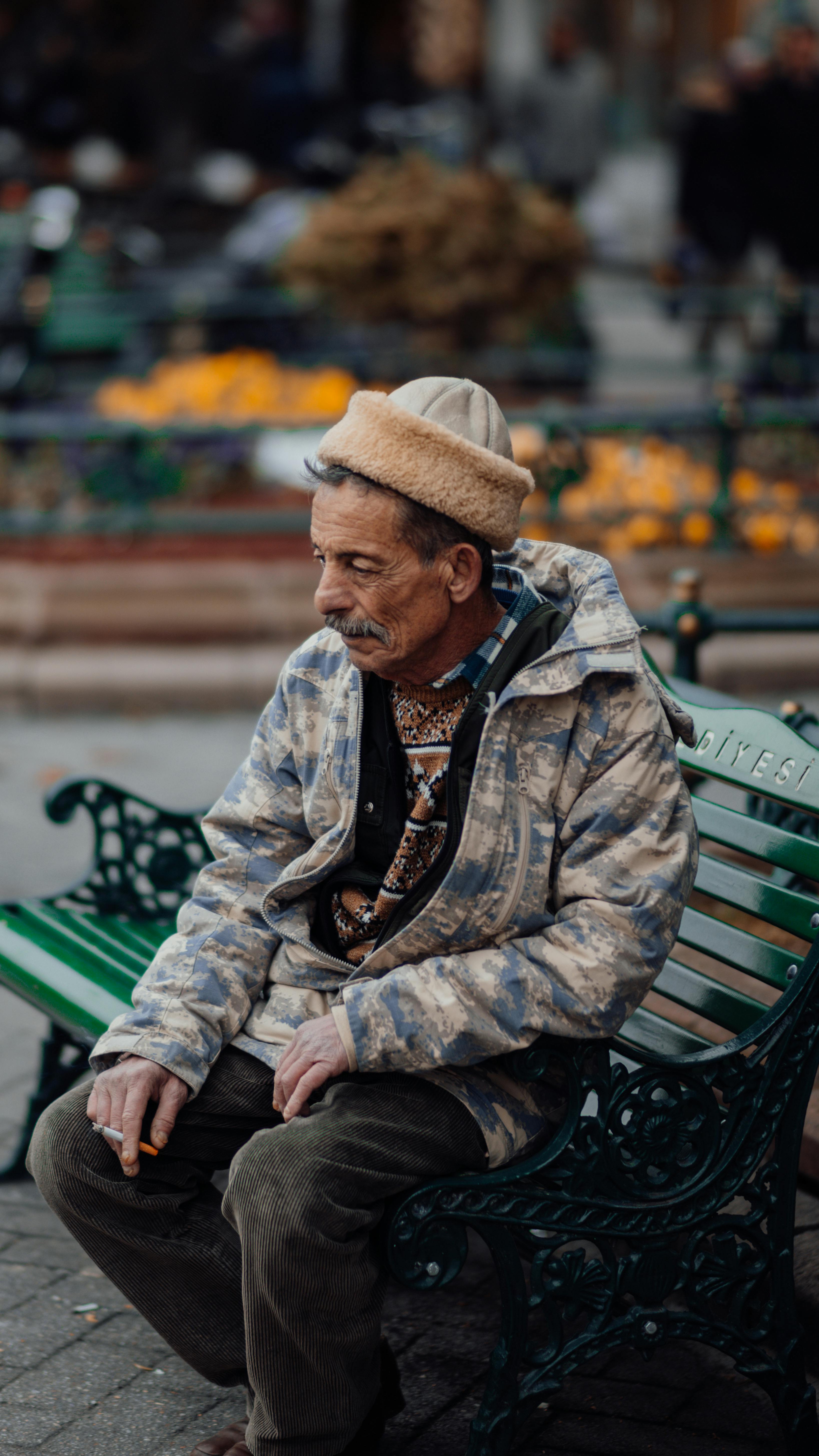 Tired Man Sitting on Green Bench and Smoking Cigarette · Free Stock Photo