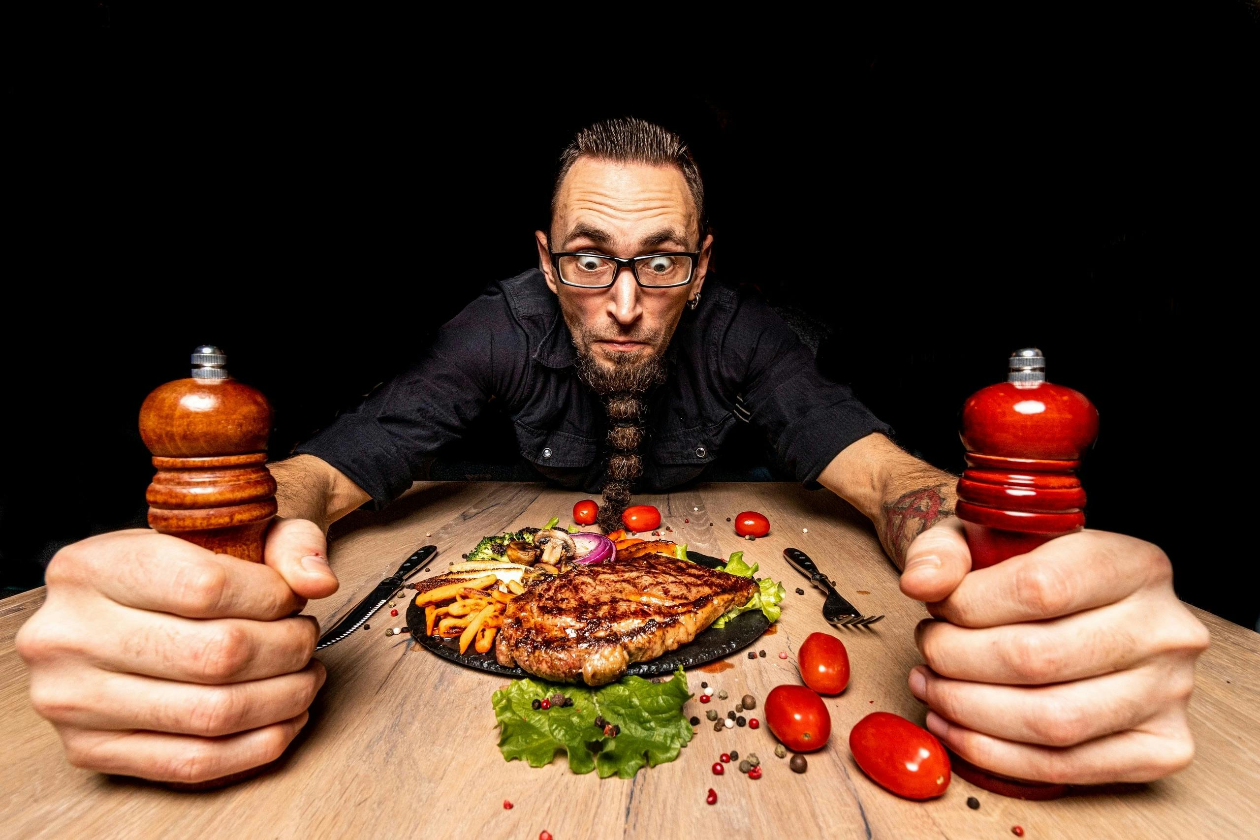 Man Holding to a Pepper and Salt Shakers Looking at the Large Steak in ...