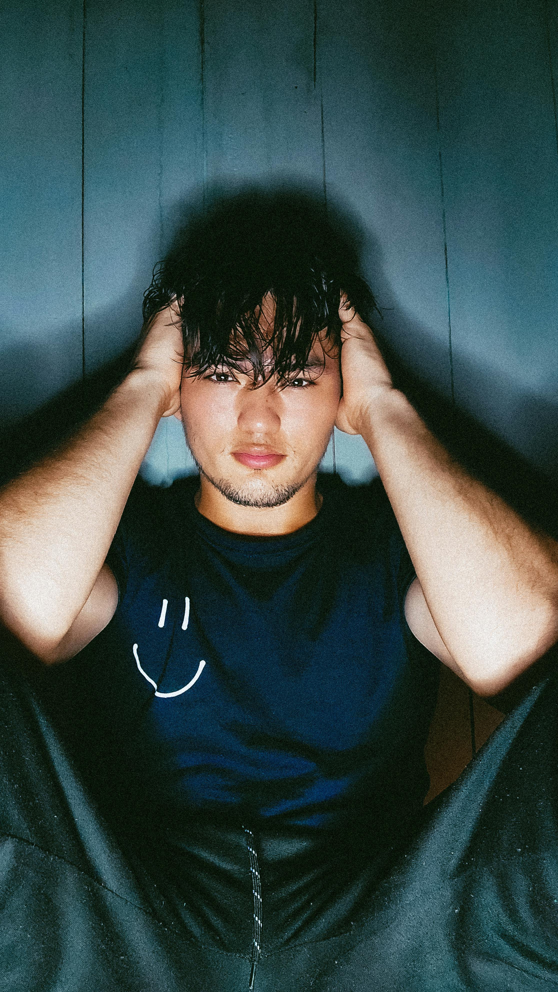 Young Man in a T-shirt with a Smiley Face Holding His Head · Free Stock ...