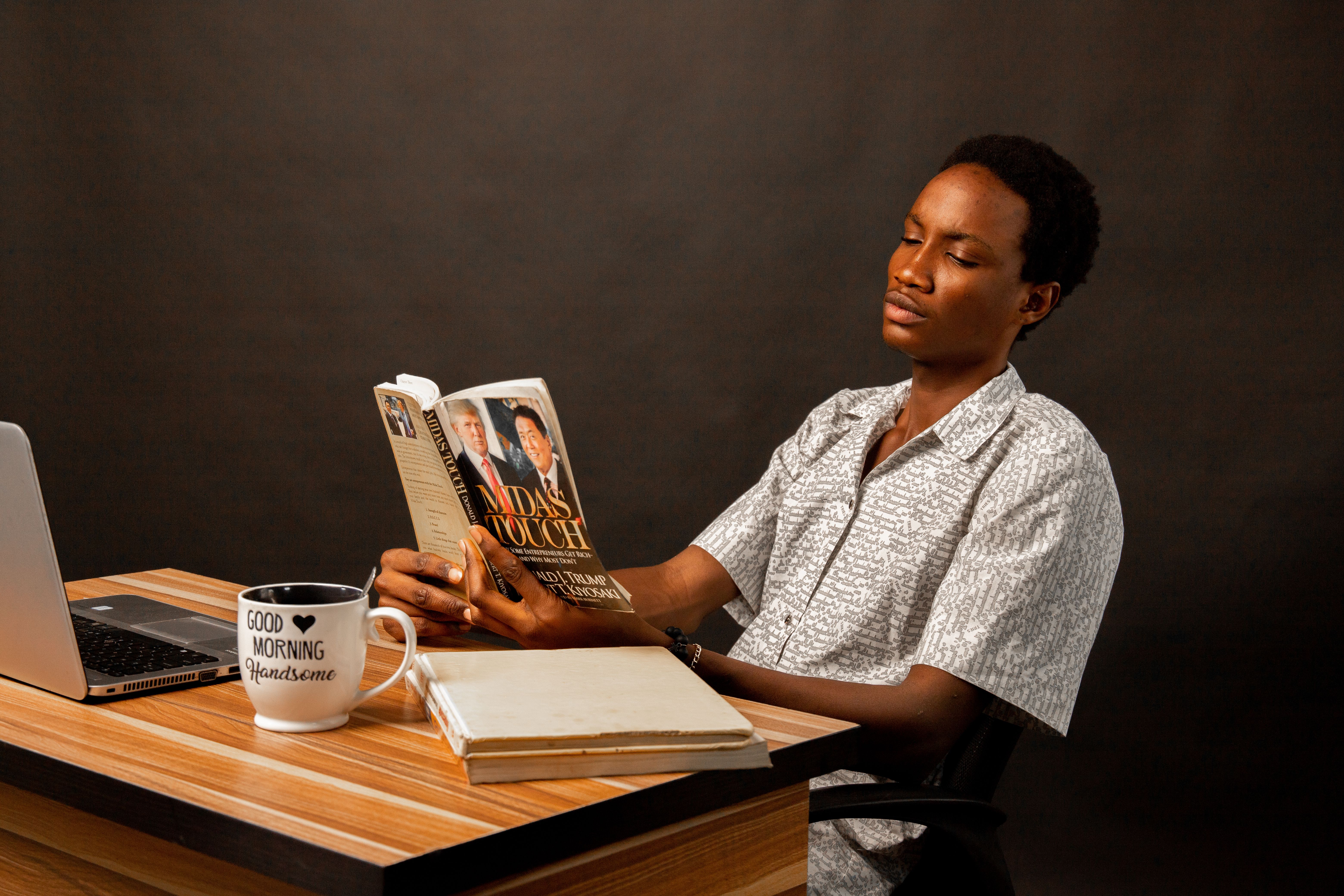 Young Man Sitting at the Desk and Reading a Book · Free Stock Photo