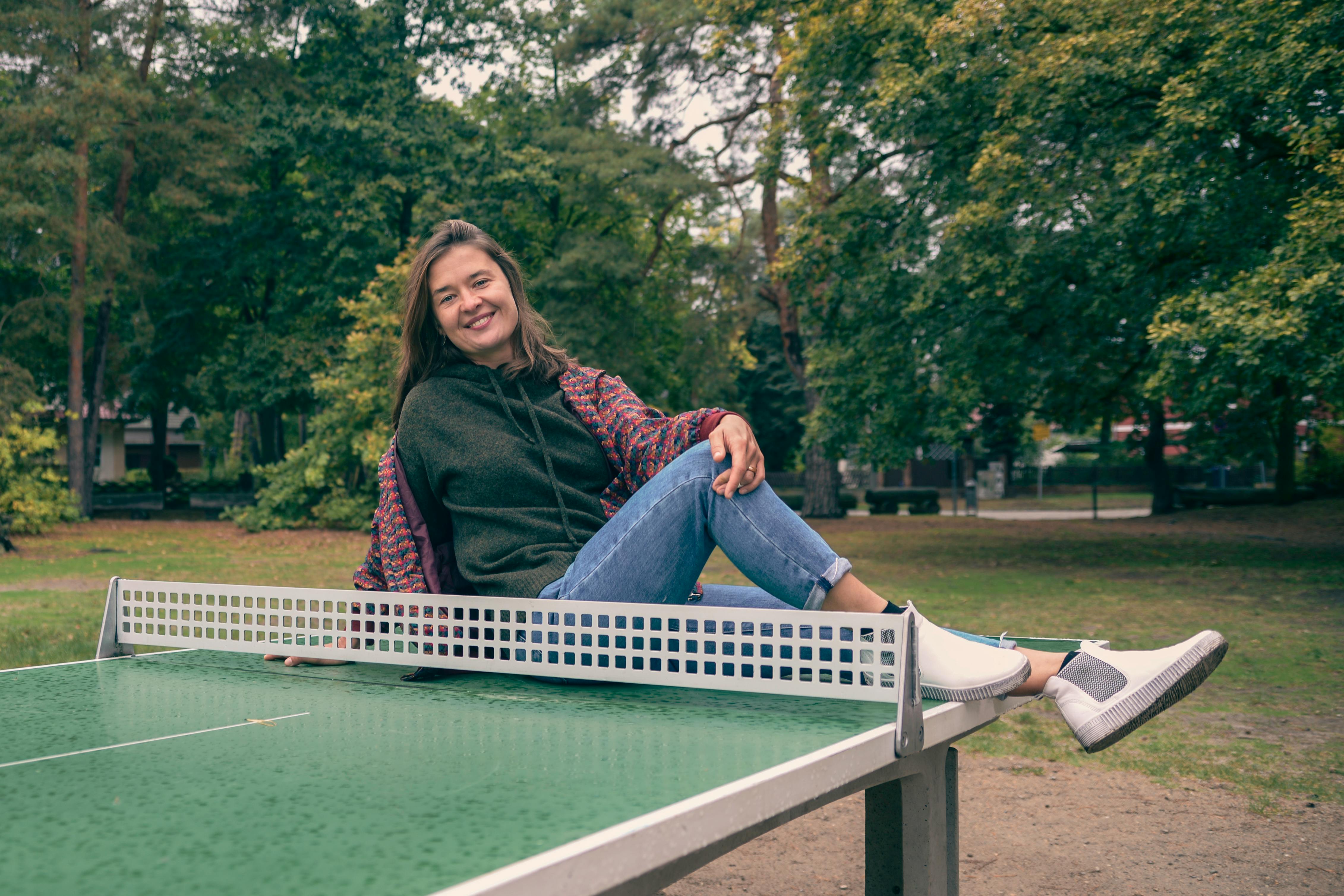 A woman sitting on top of a ping pong table · Free Stock Photo