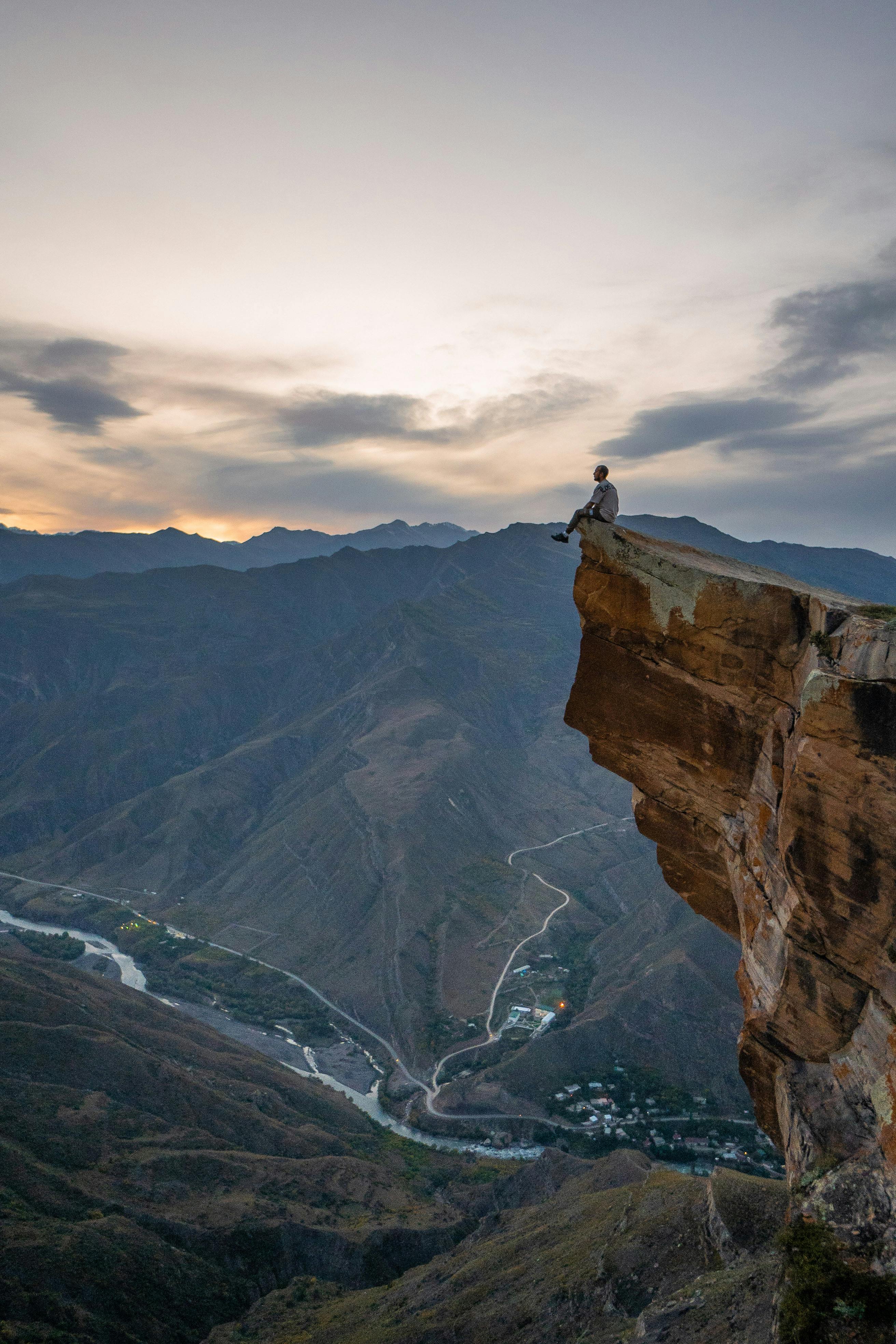Man Sitting on Rock Edge over Valley at Sunset · Free Stock Photo