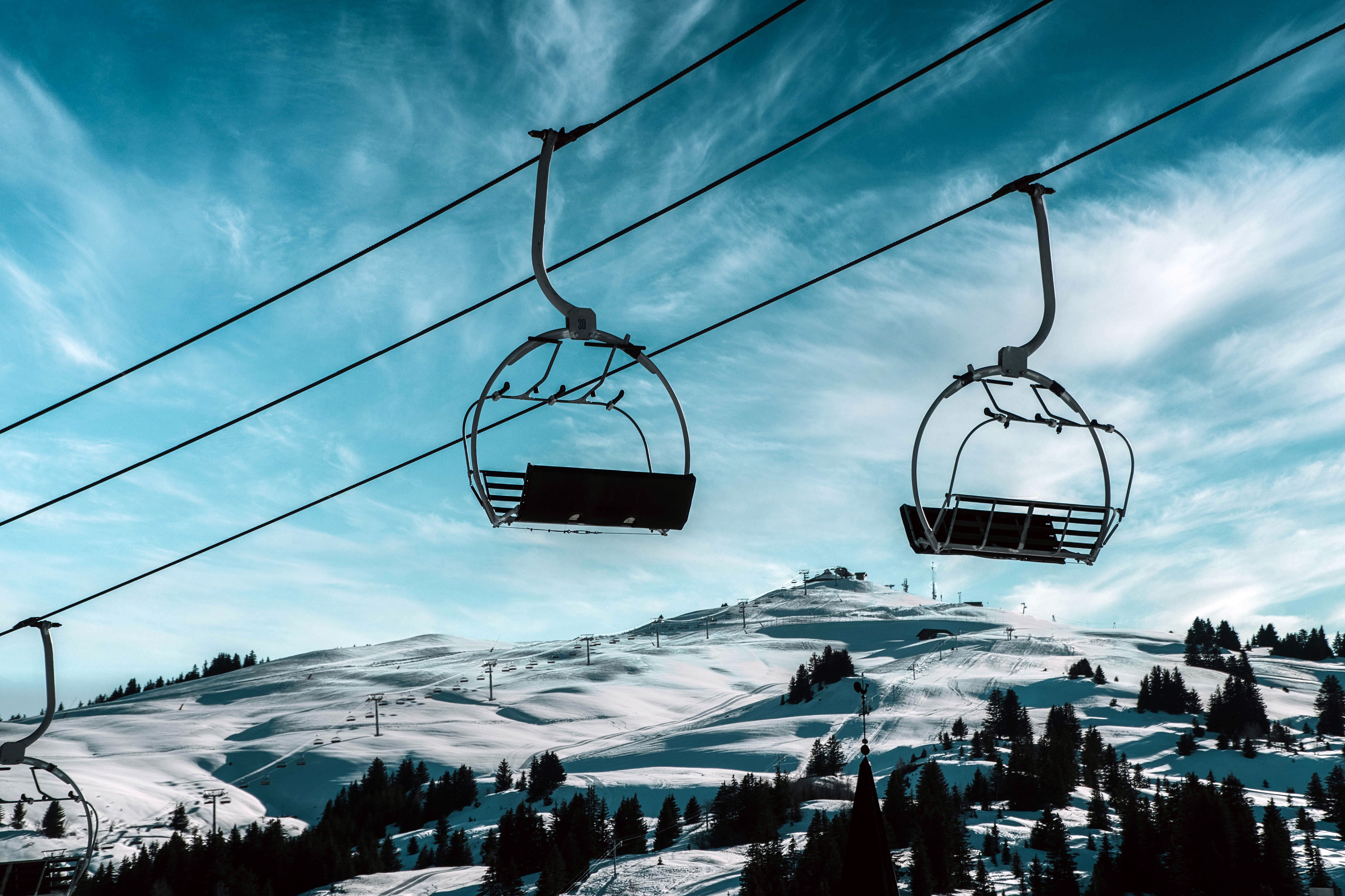 Two ski lifts are sitting on top of a snowy hill · Free Stock Photo