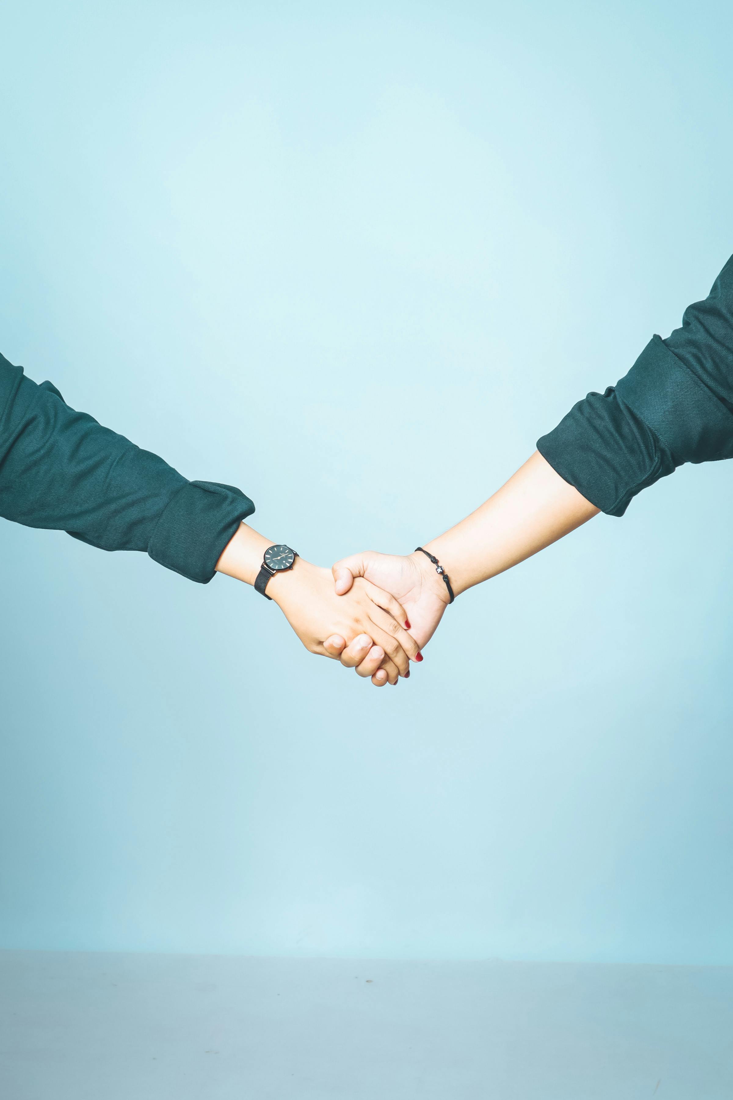 Holding Hands Against Blue Background · Free Stock Photo