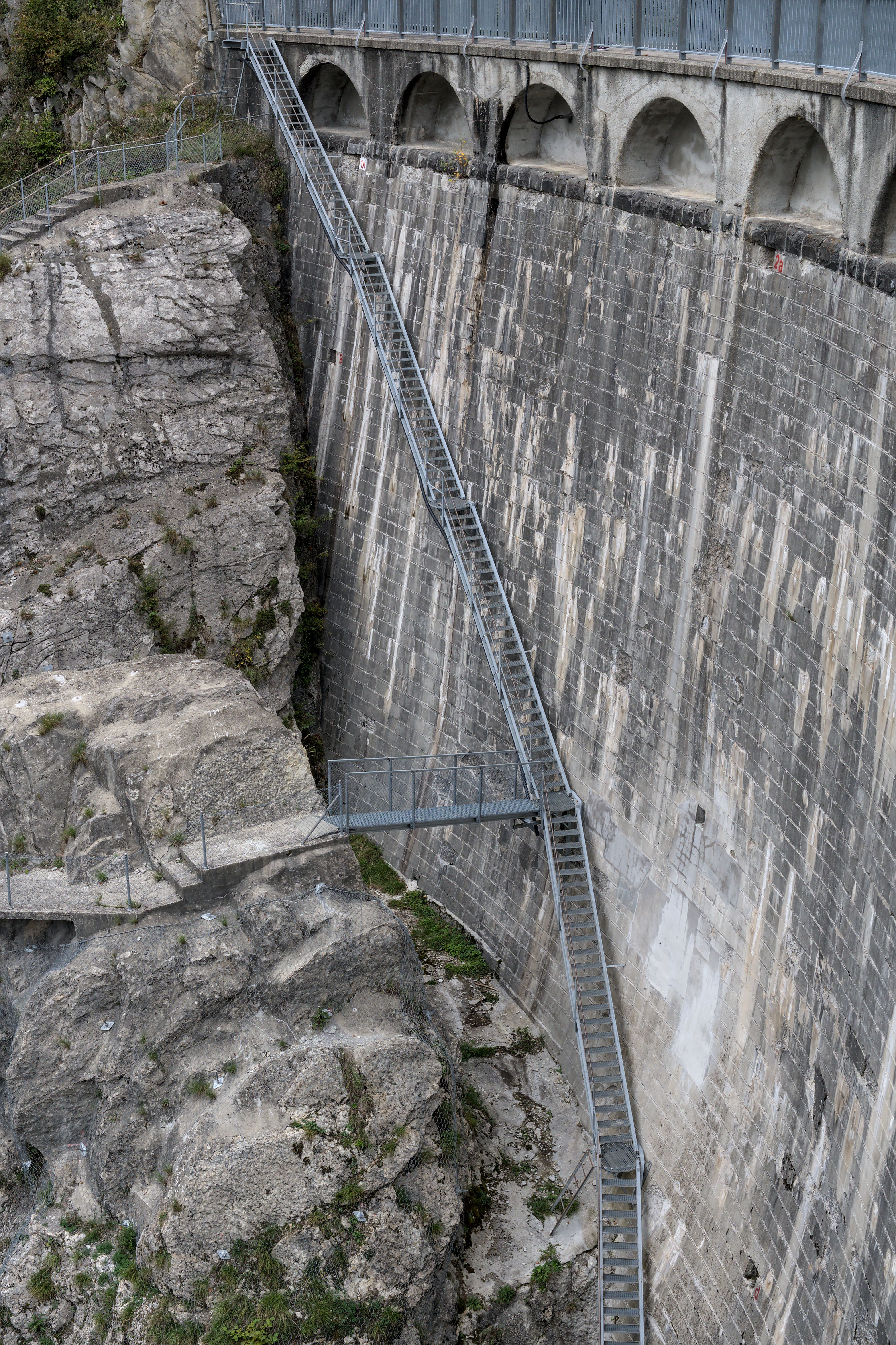 A bridge over a large dam with a large rock · Free Stock Photo