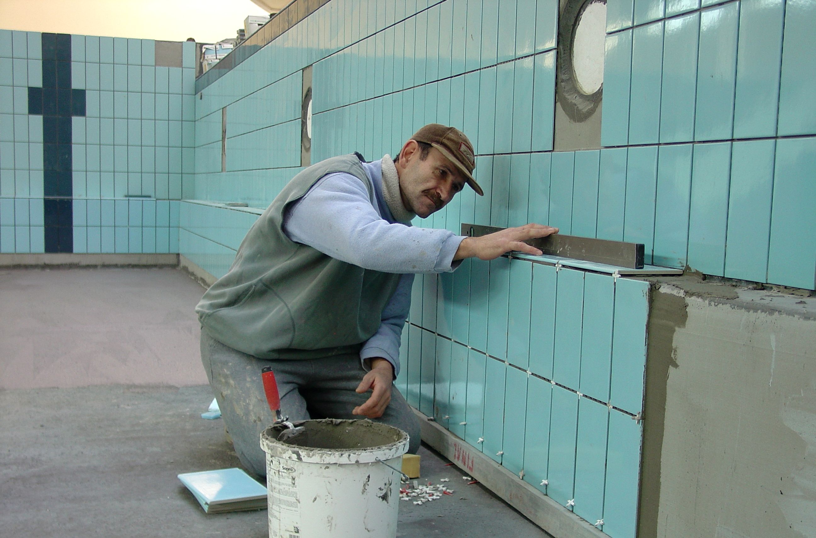A man is working on a wall with tiles · Free Stock Photo