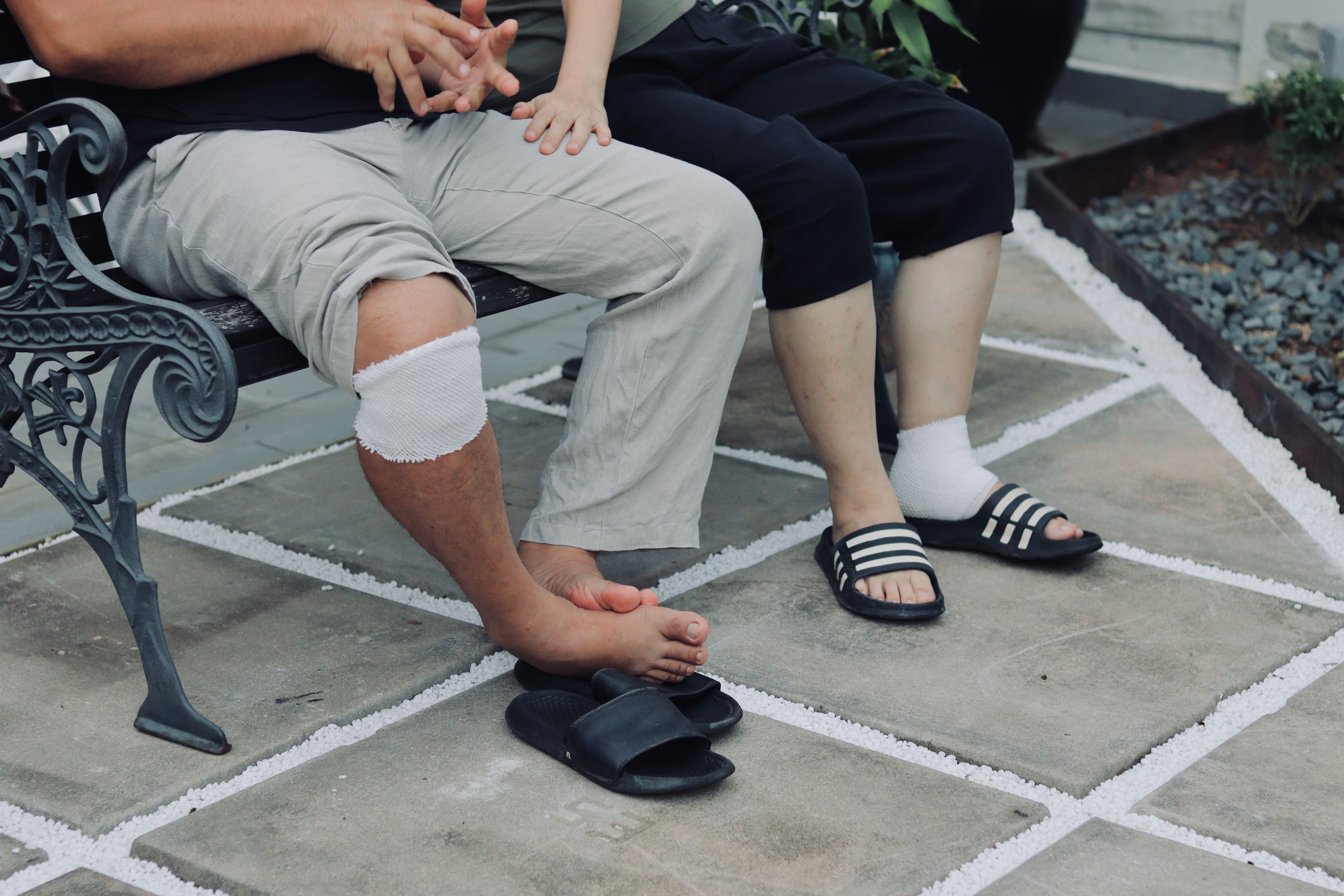 Bandaged Legs of a Couple Sitting on a Bench · Free Stock Photo