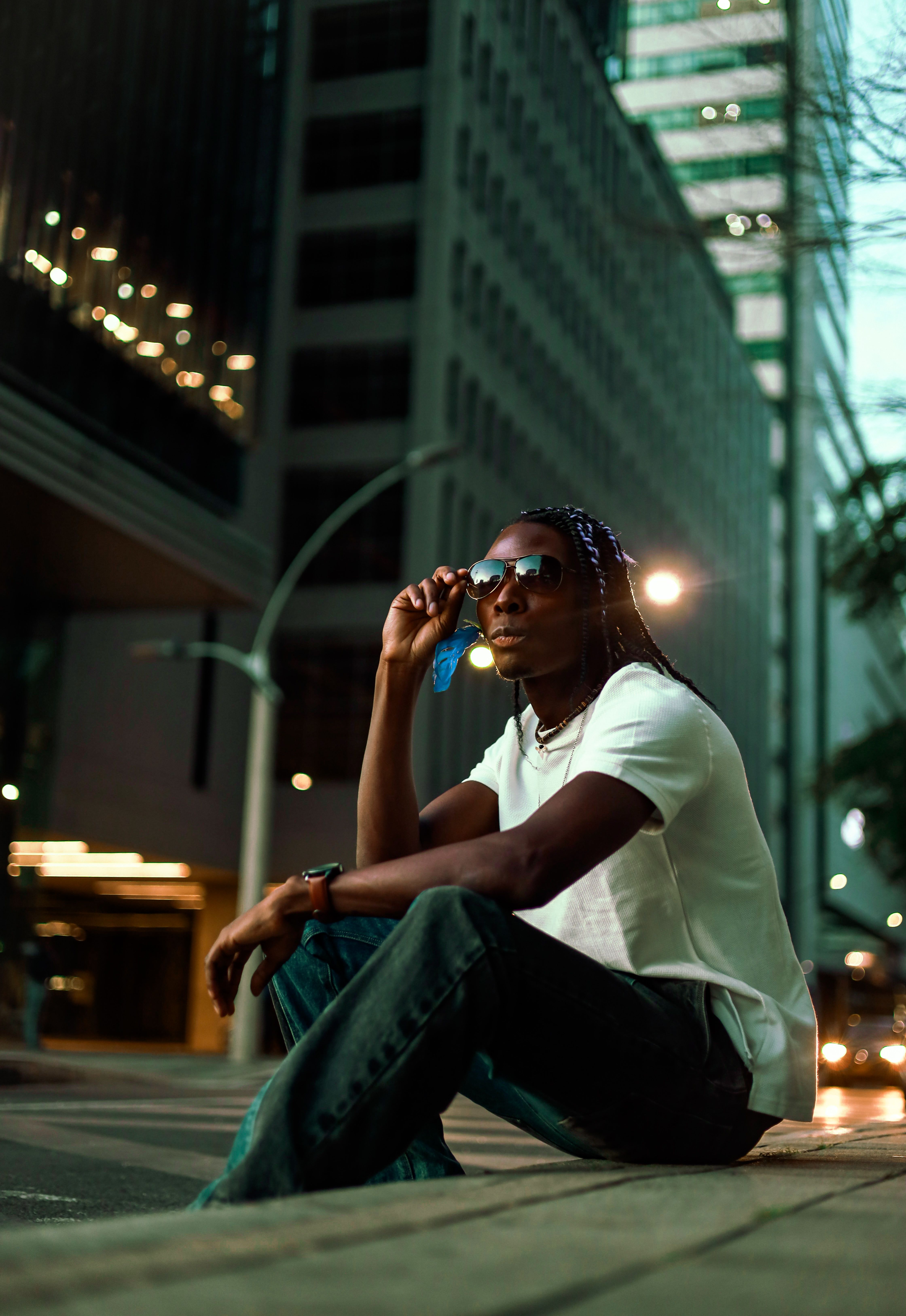 A Man Sitting on a Curb by the Street in City · Free Stock Photo
