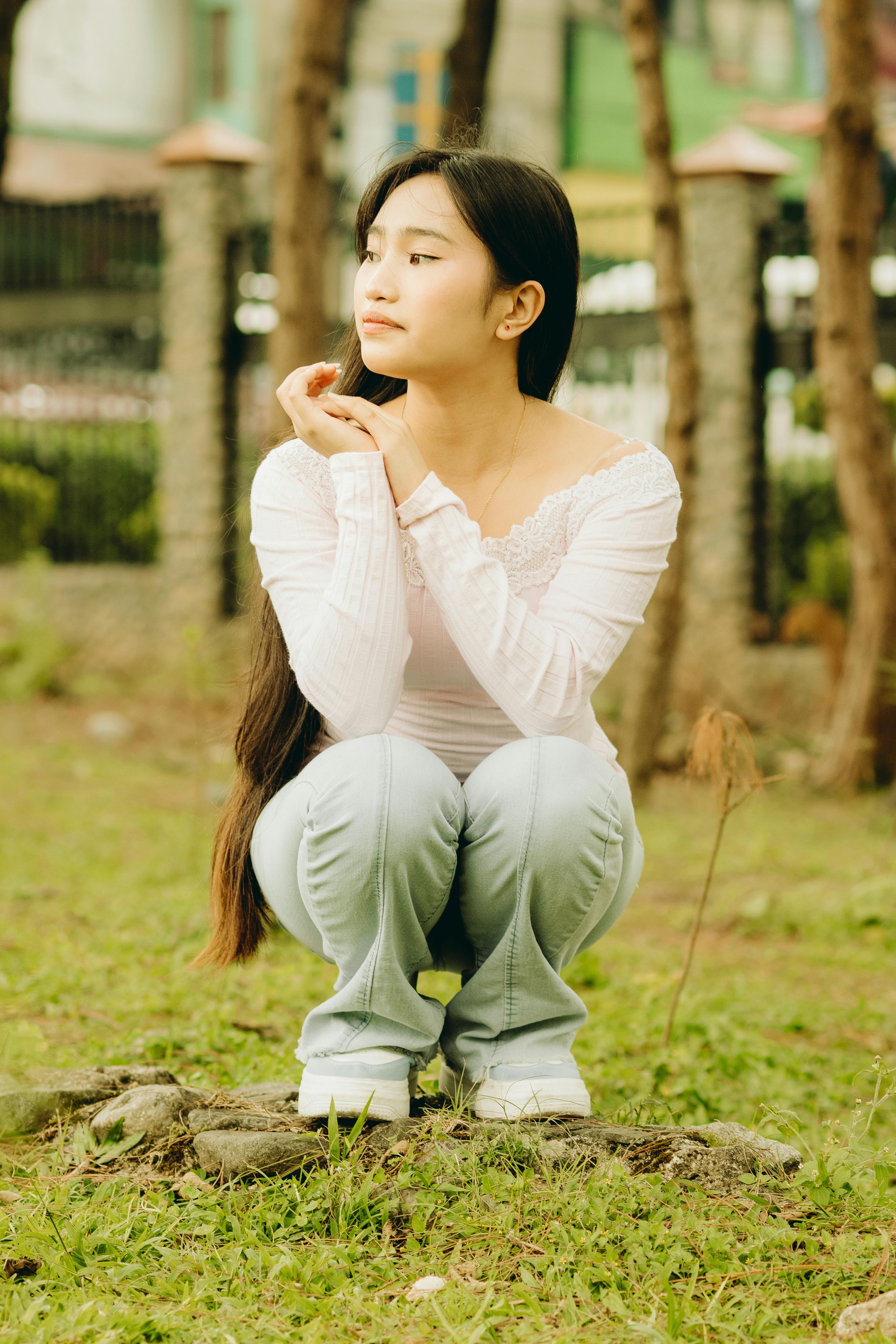 Young Brunette Crouching in Jeans · Free Stock Photo
