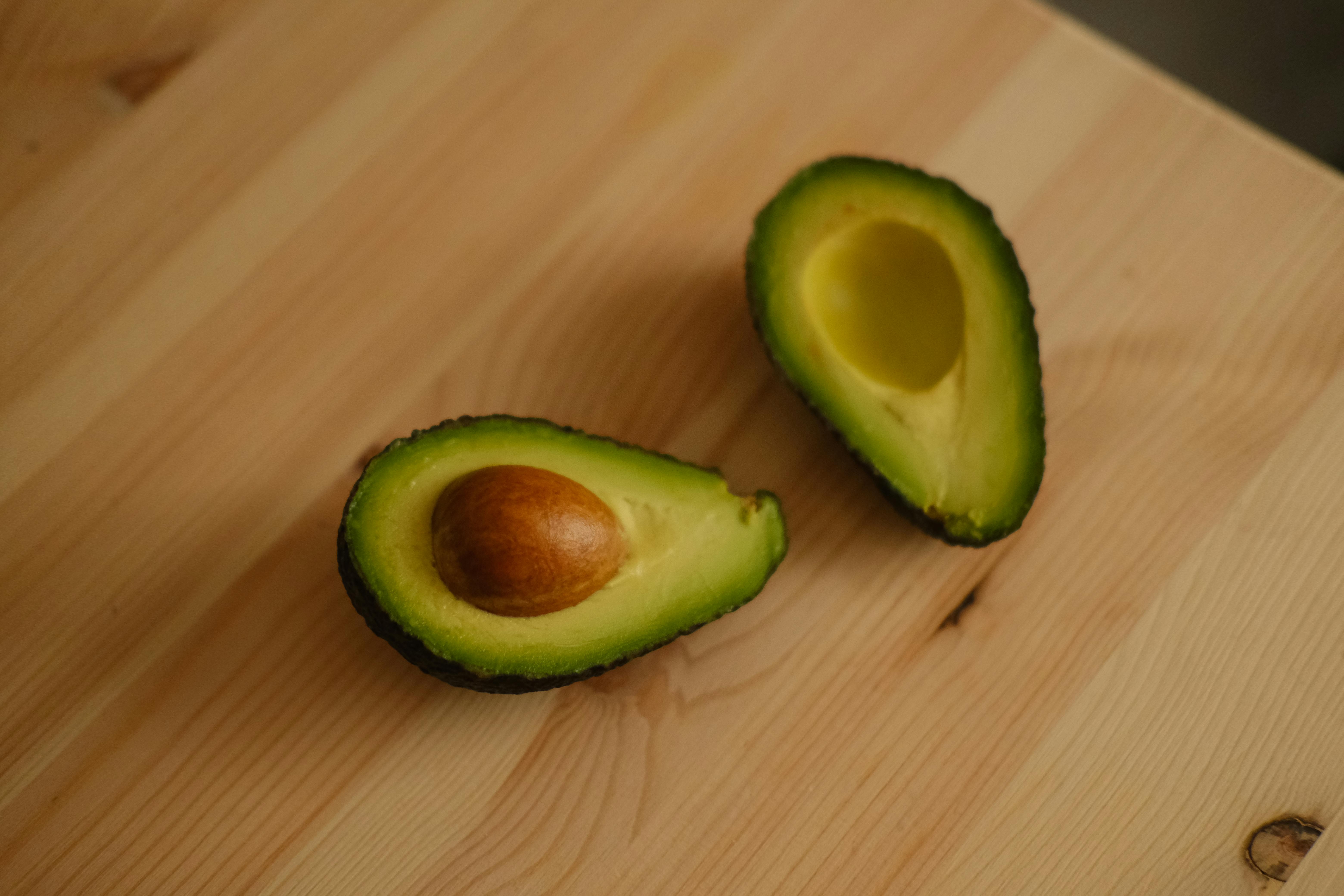 Photo of a Halved Avocado on a Wooden Table · Free Stock Photo