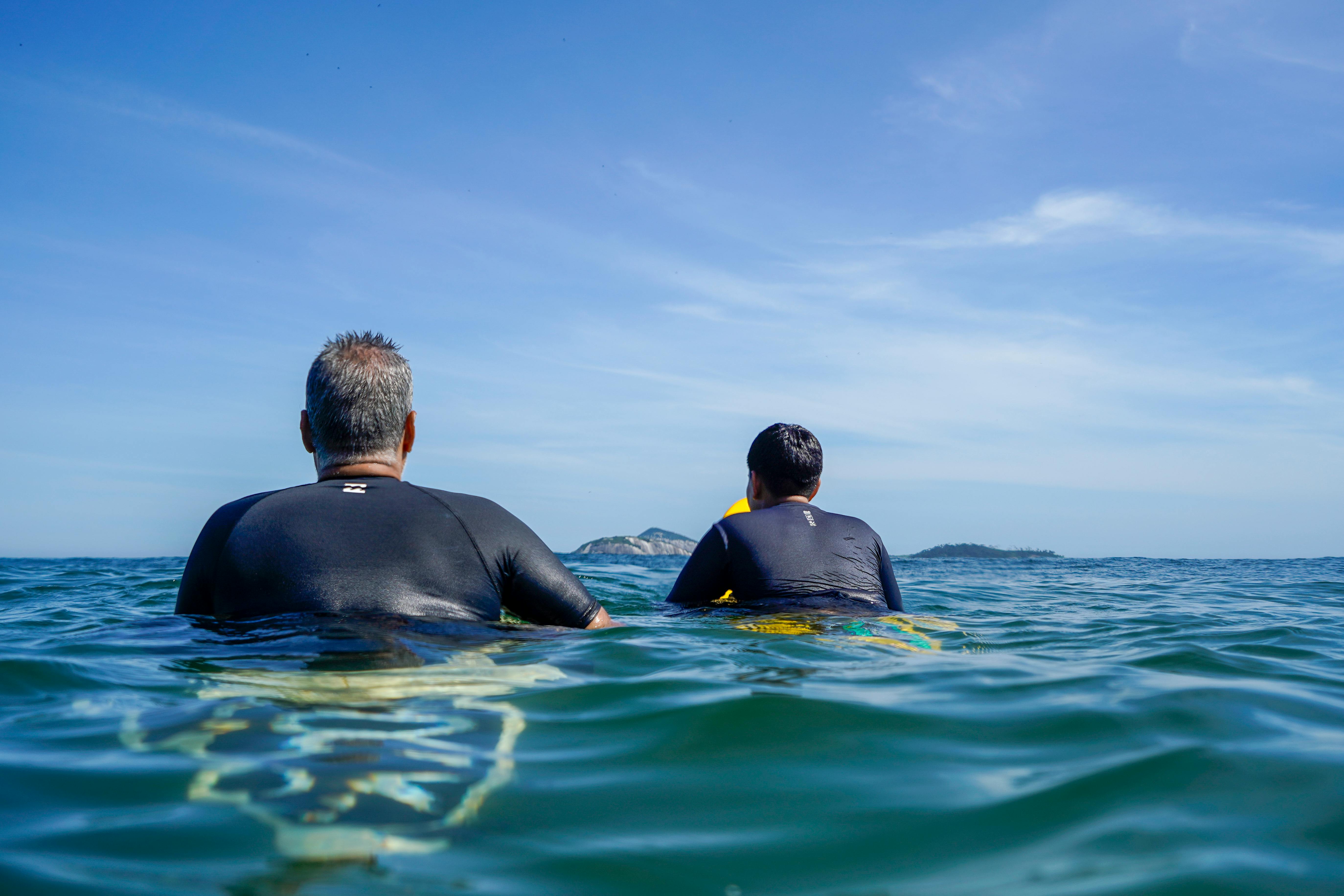 Men in Wetsuits Swimming in the Sea · Free Stock Photo