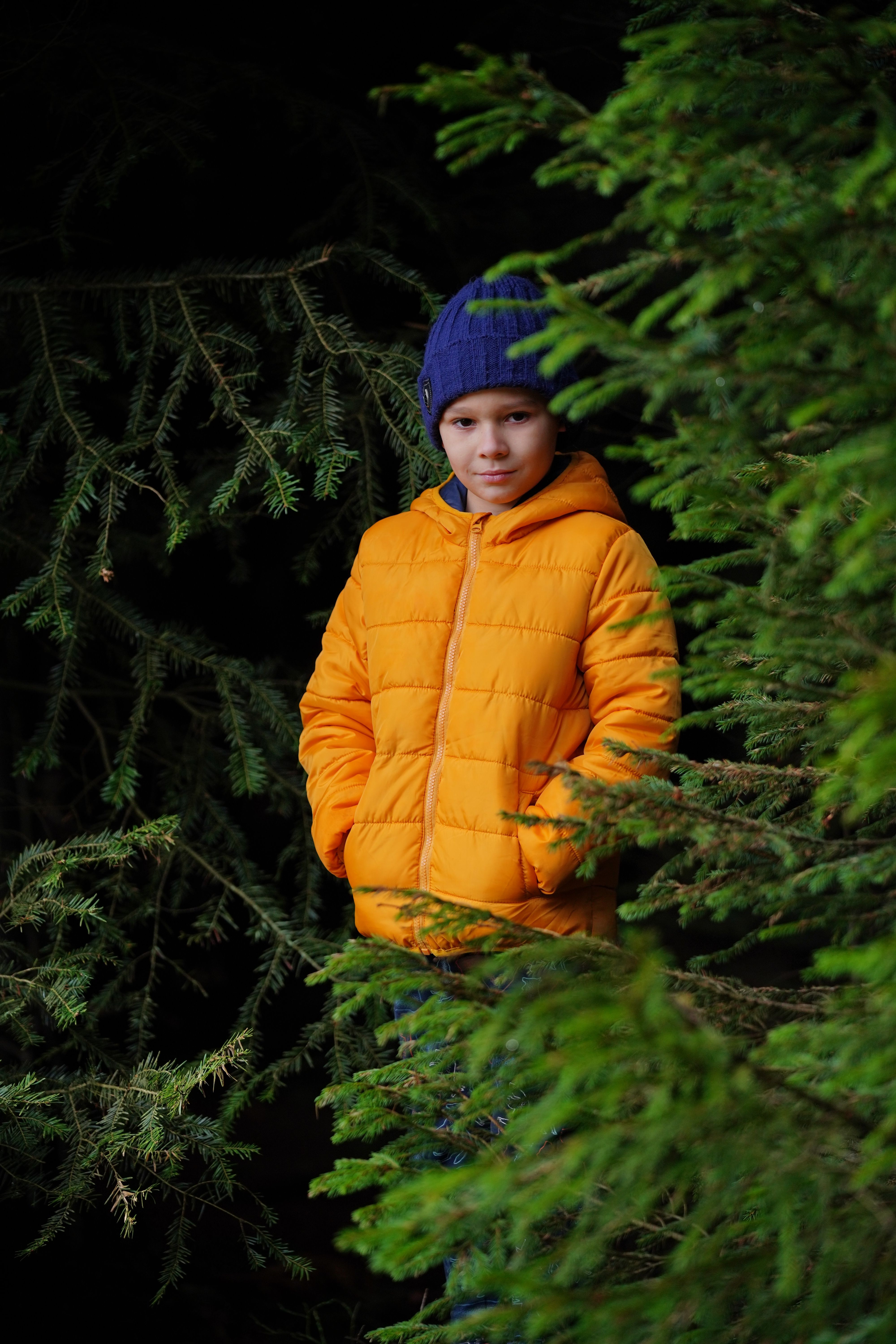 Young Boy in a Yellow Winter Jacket and a Cap Standing with his Hands ...