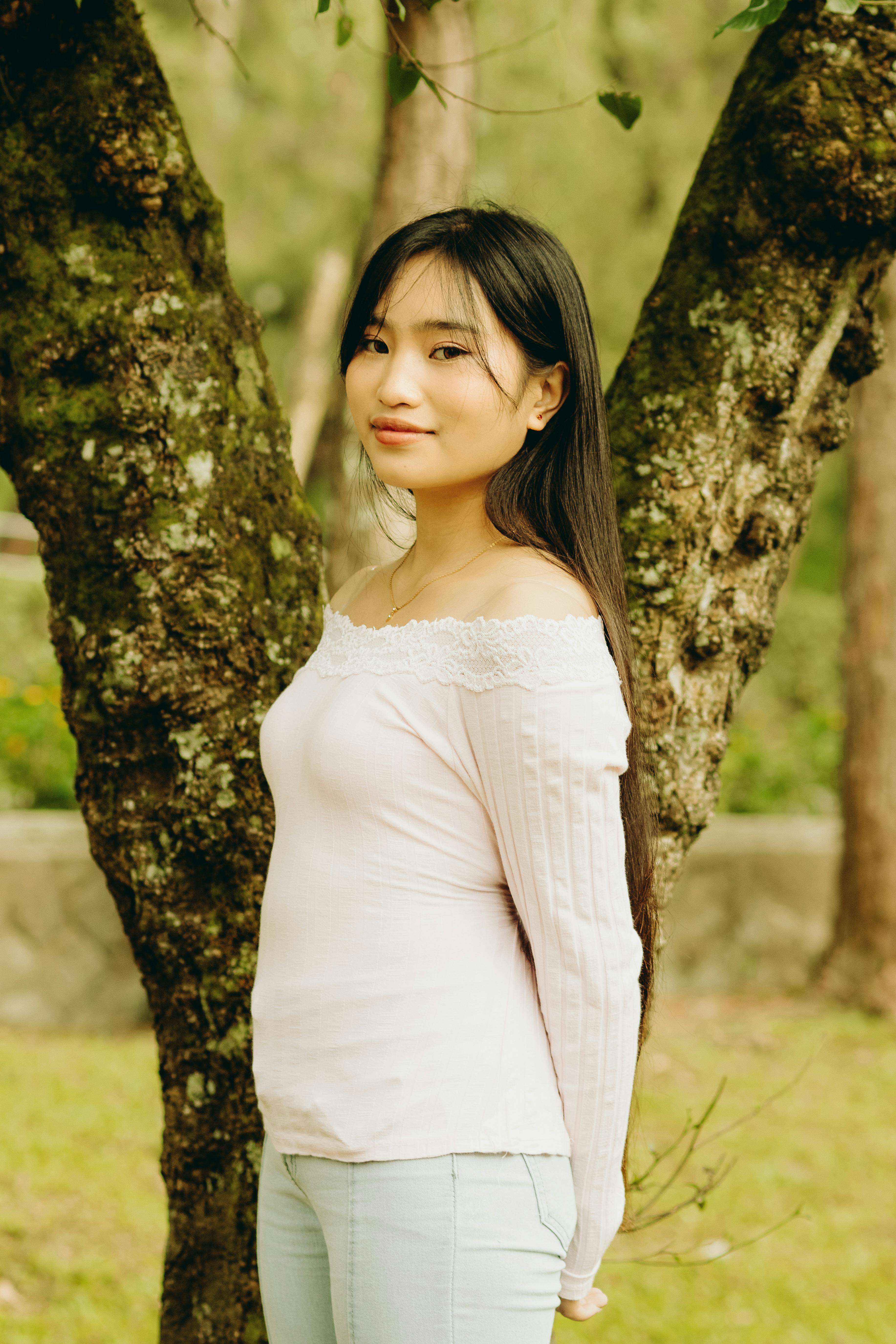 Modest Brunette Standing by Tree · Free Stock Photo