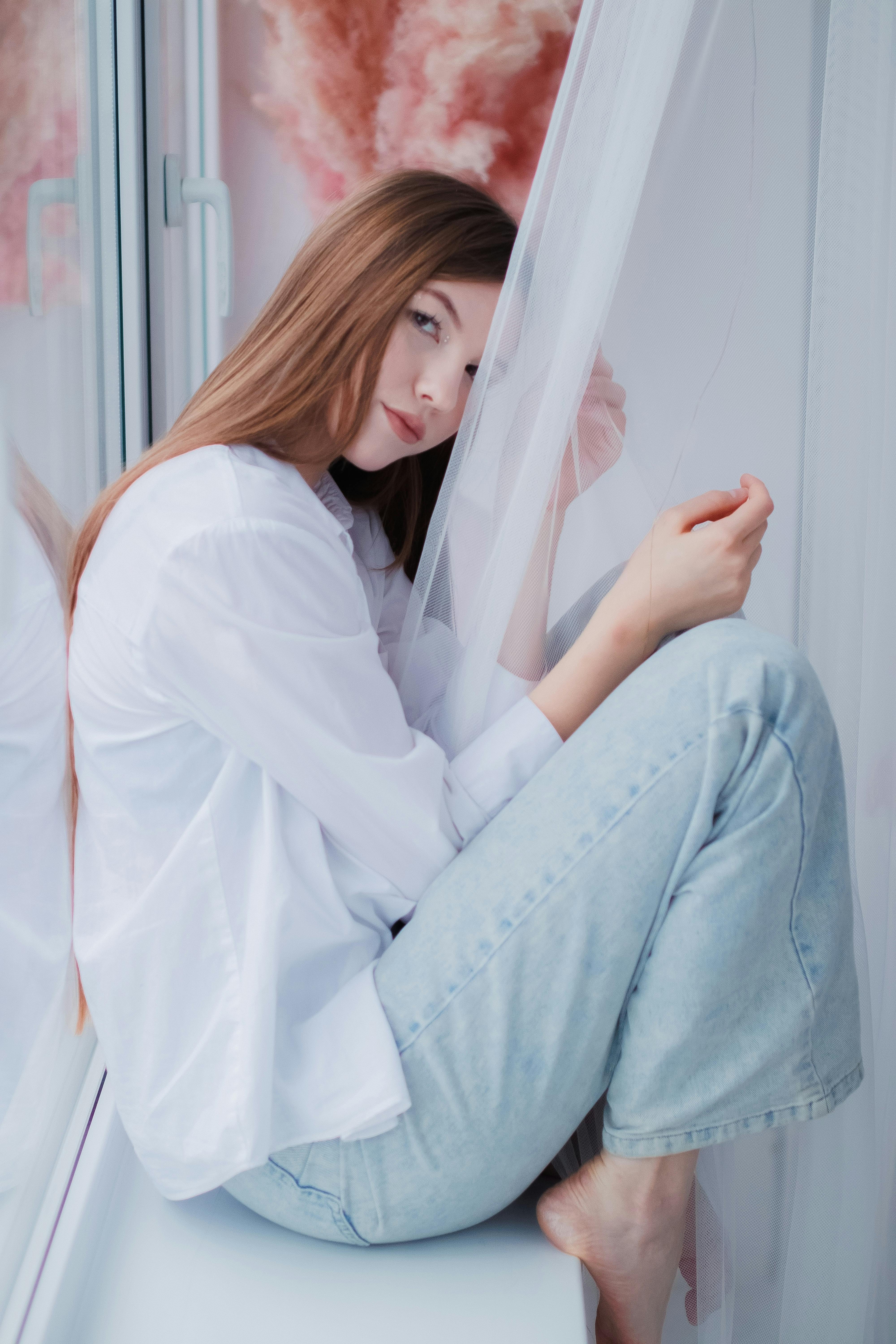 Woman in White Shirt and Jeans Sitting on Windowsill · Free Stock Photo