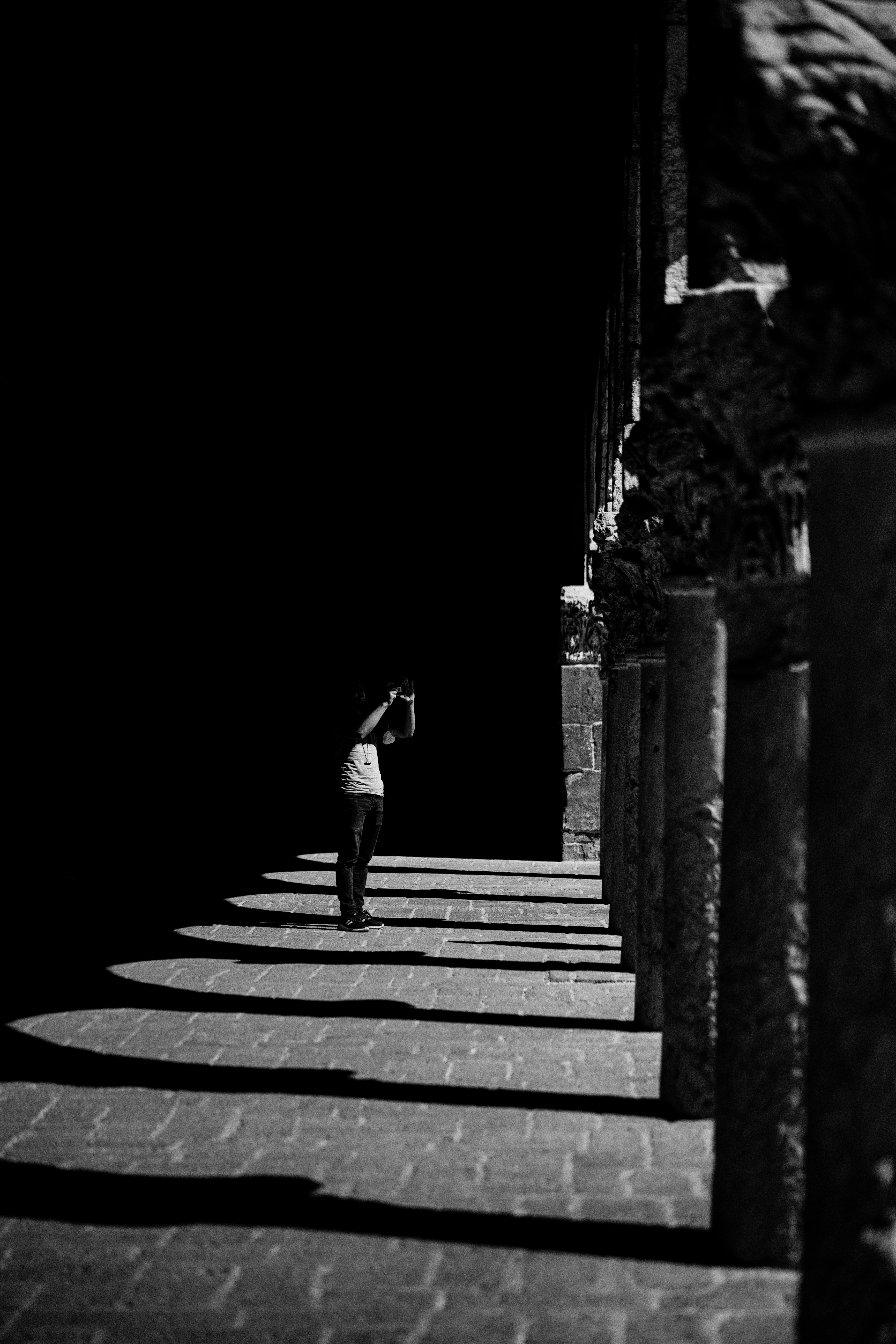 A Person Standing in the Shadows of an Arcade · Free Stock Photo