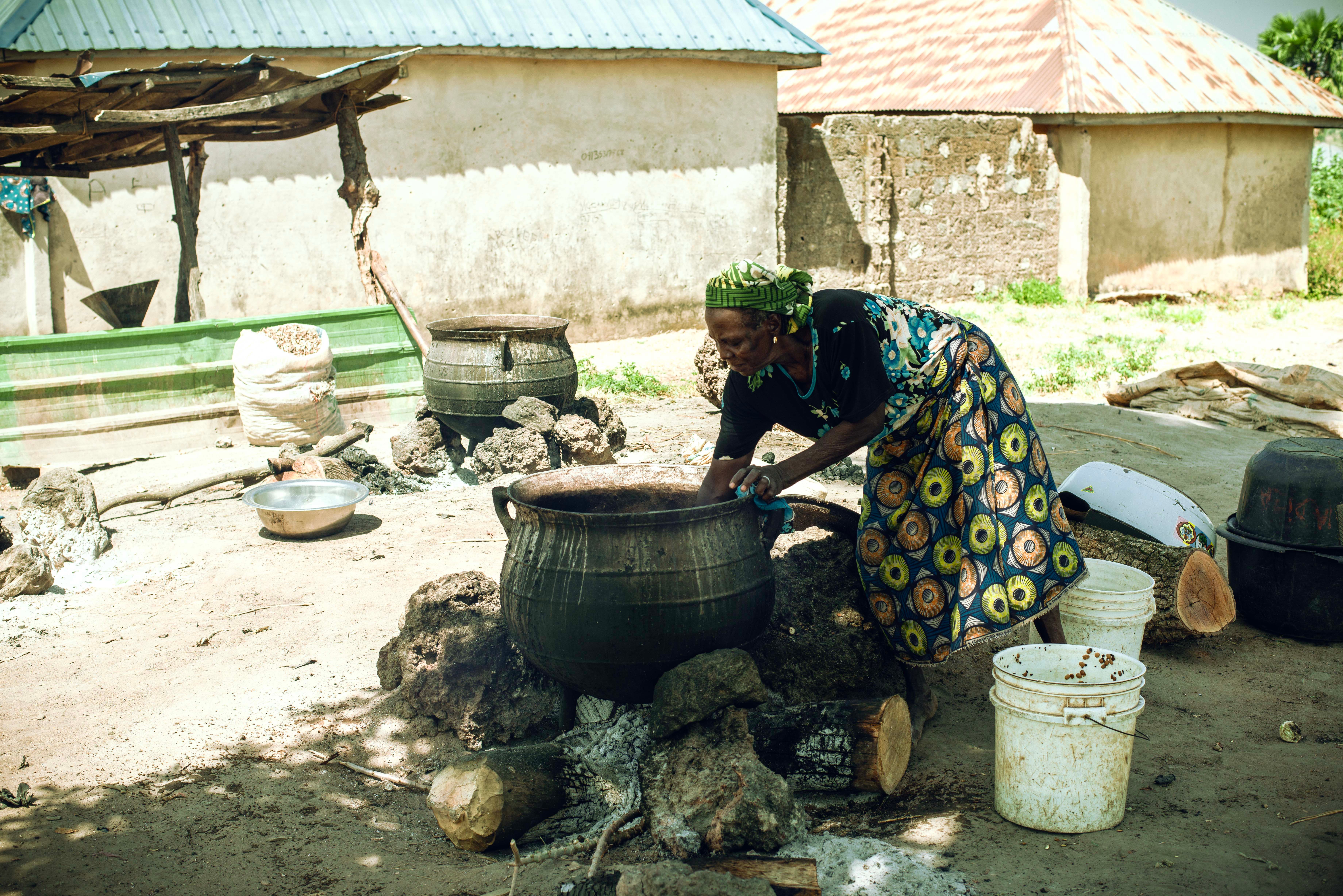 Woman Cleaning a Large Cauldron in the Yard · Free Stock Photo