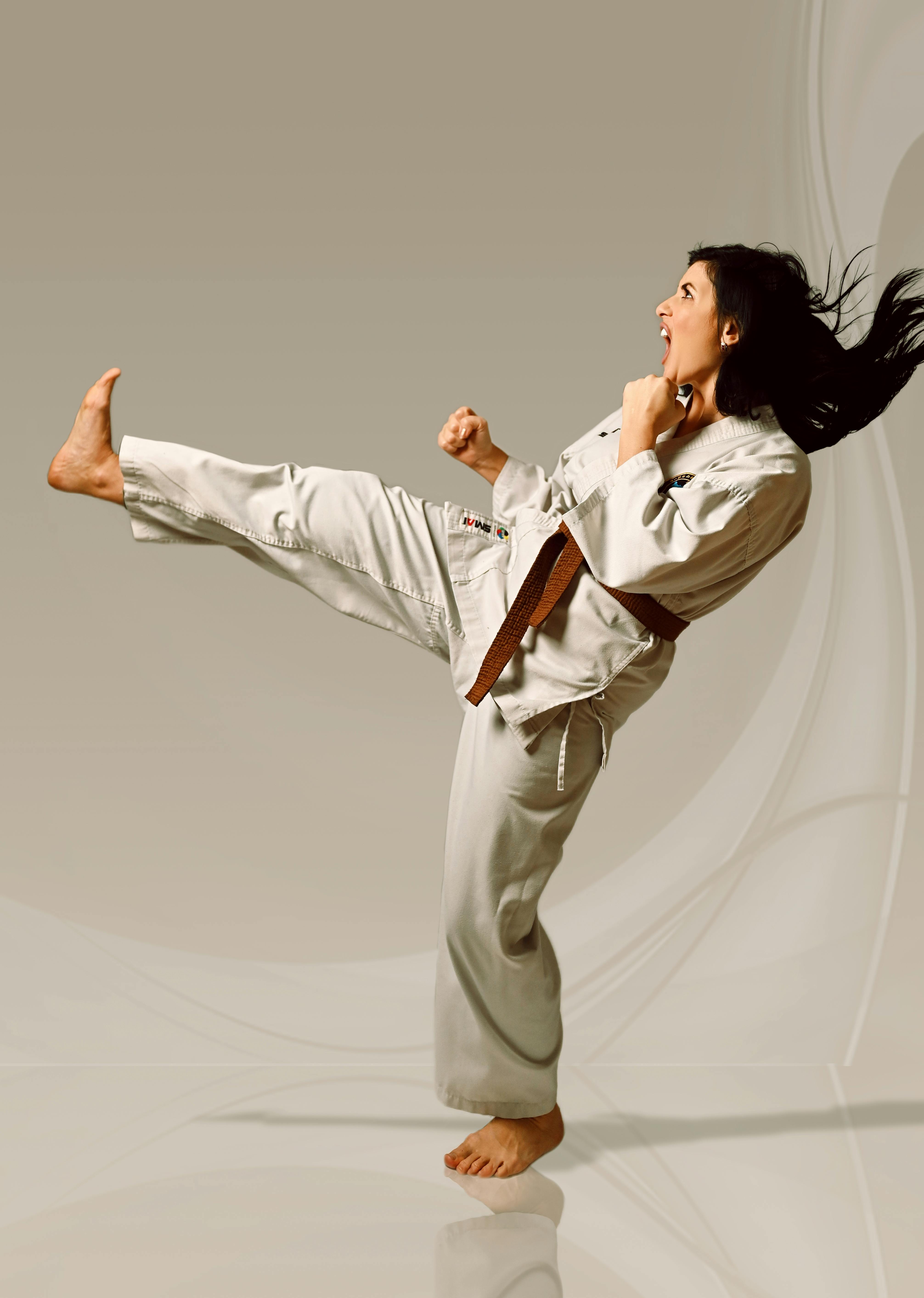 Woman in a Kimono with a Brown Belt Doing a Kick · Free Stock Photo
