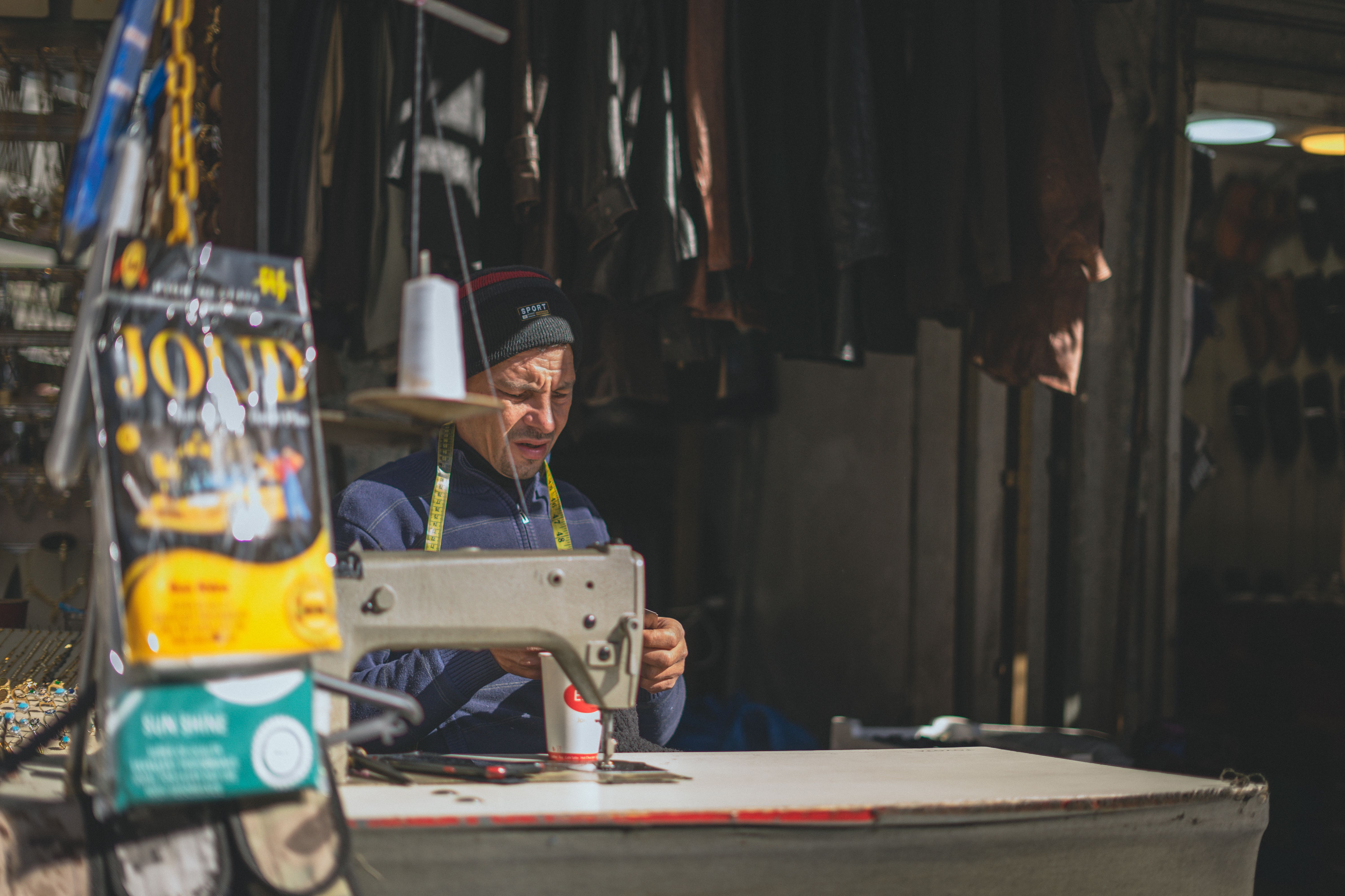 Man at a Market Stall Using a Sewing Machine · Free Stock Photo