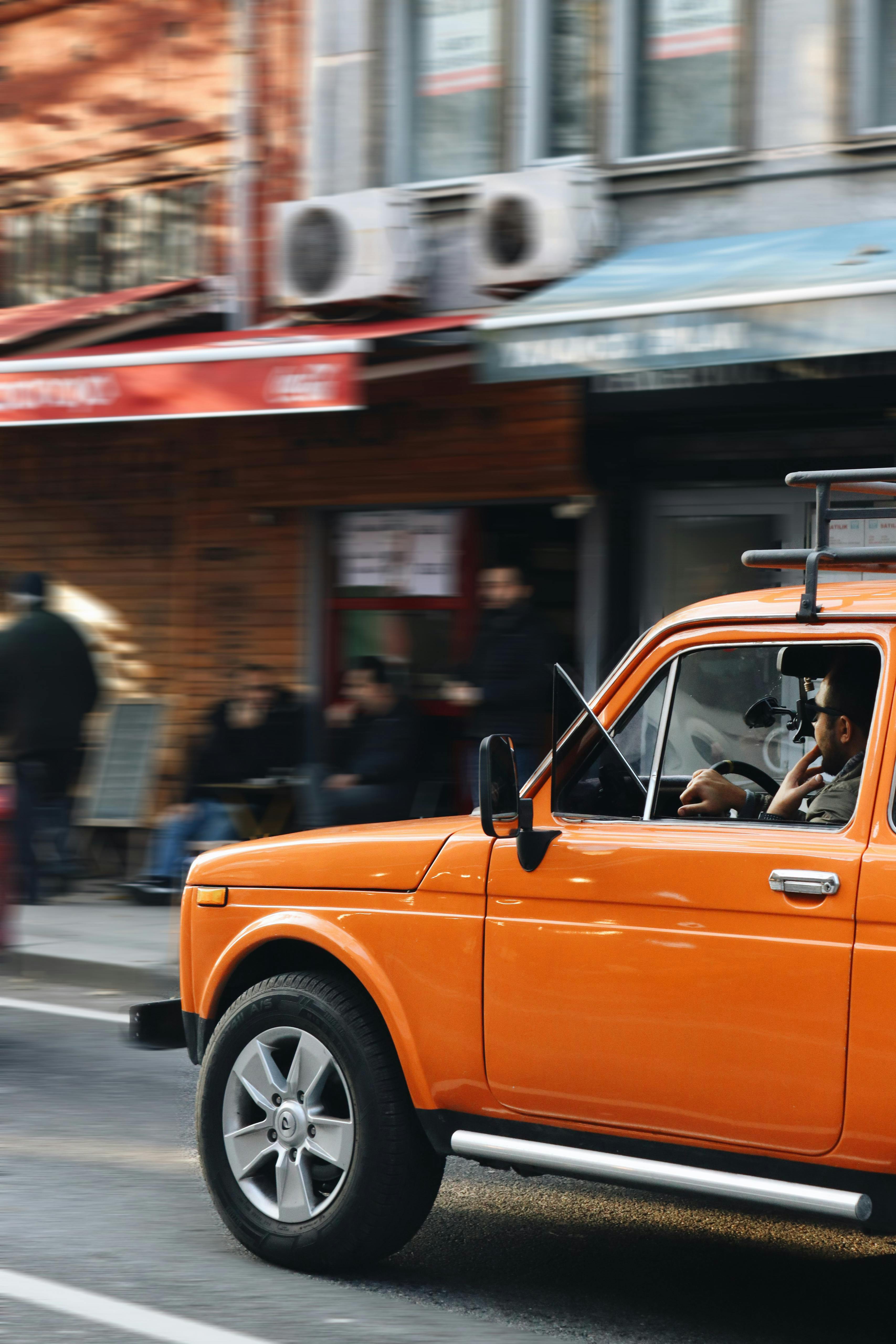 An Orange Car Driving on the Street in City · Free Stock Photo