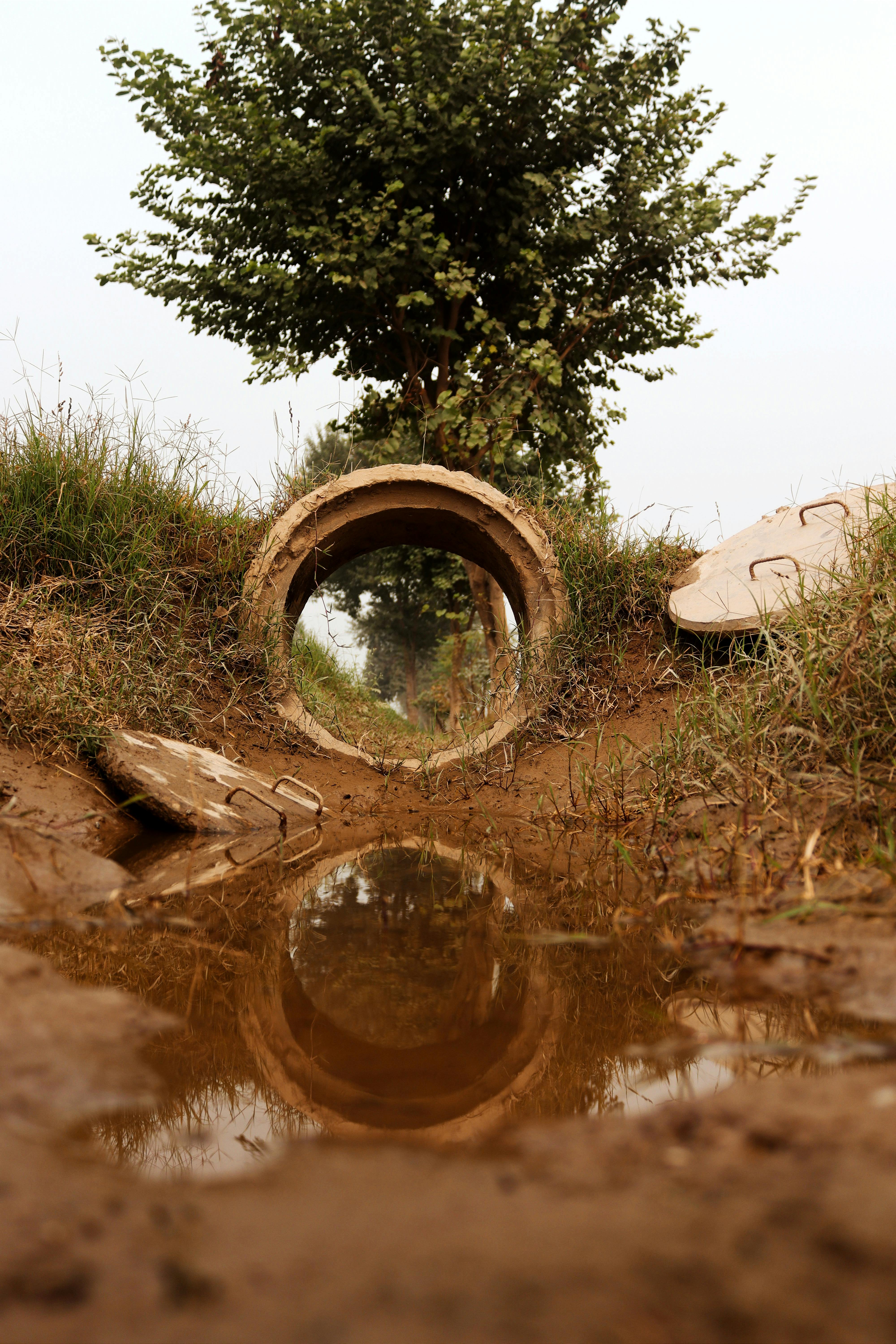 Puddle on Ground with Pipe behind · Free Stock Photo