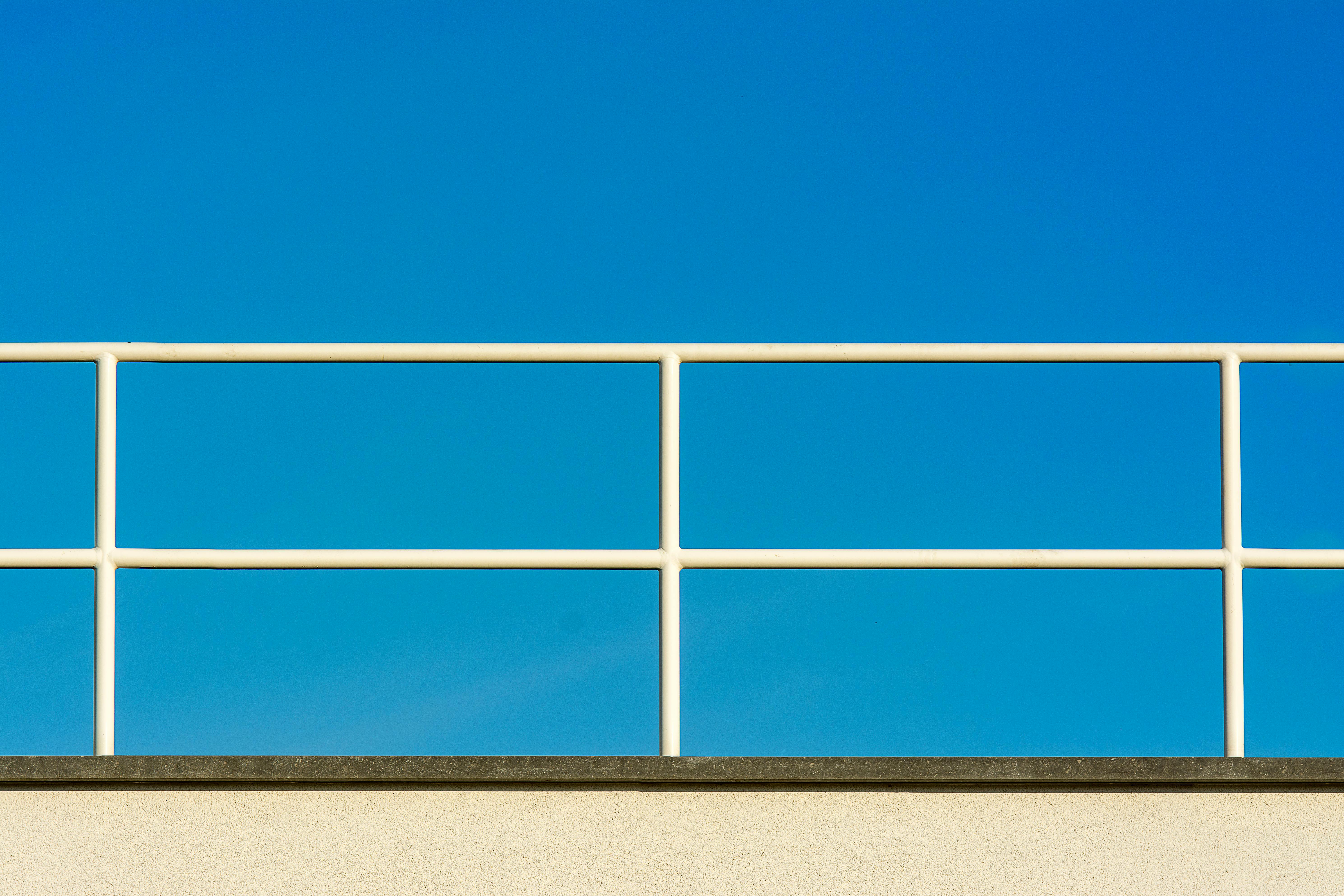 A railing on a building with a blue sky · Free Stock Photo