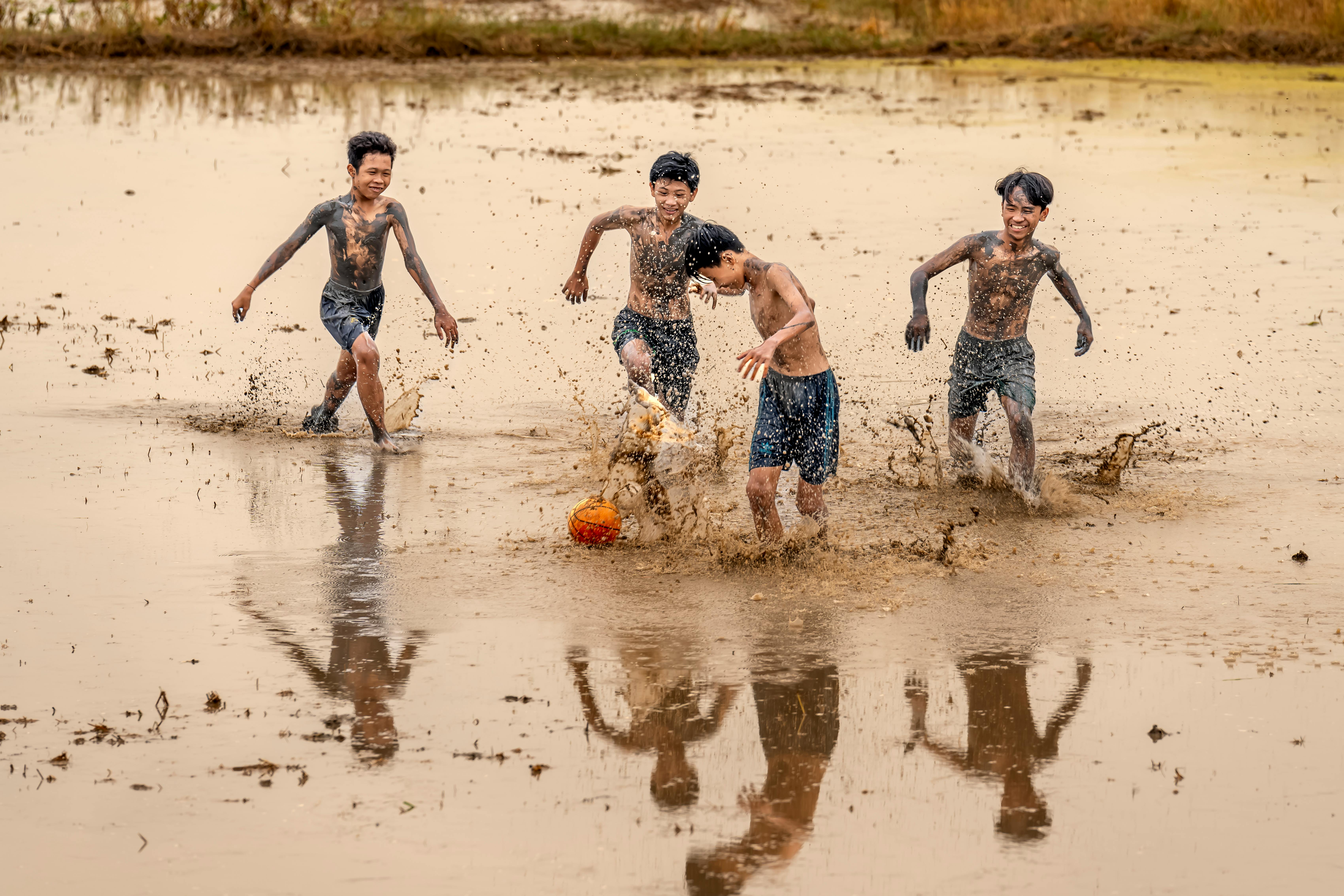 Children Playing Football in a Muddy Field · Free Stock Photo