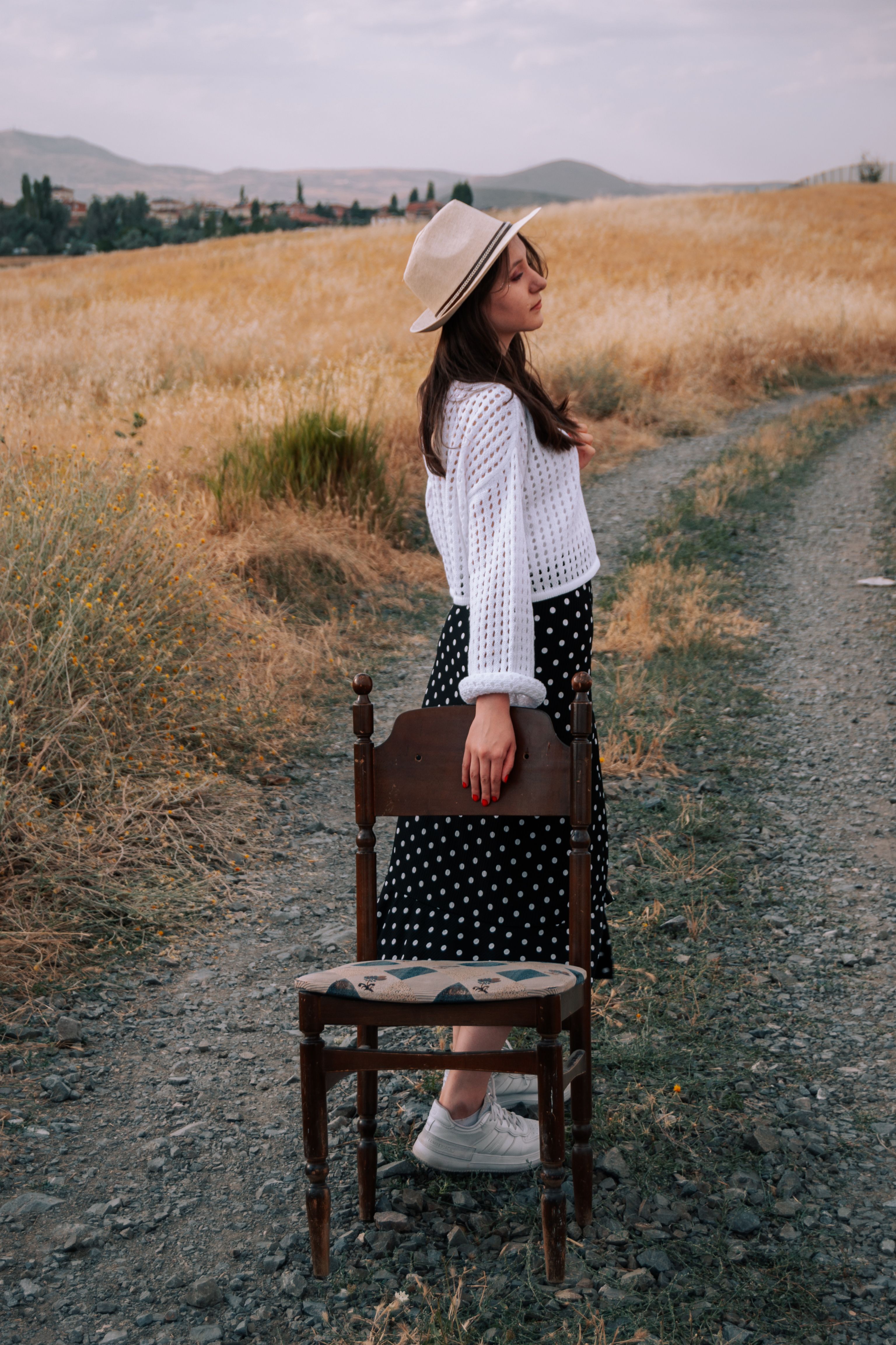 Model in a Perforated White Sweater and Polka Dot Skirt with Chair on a ...