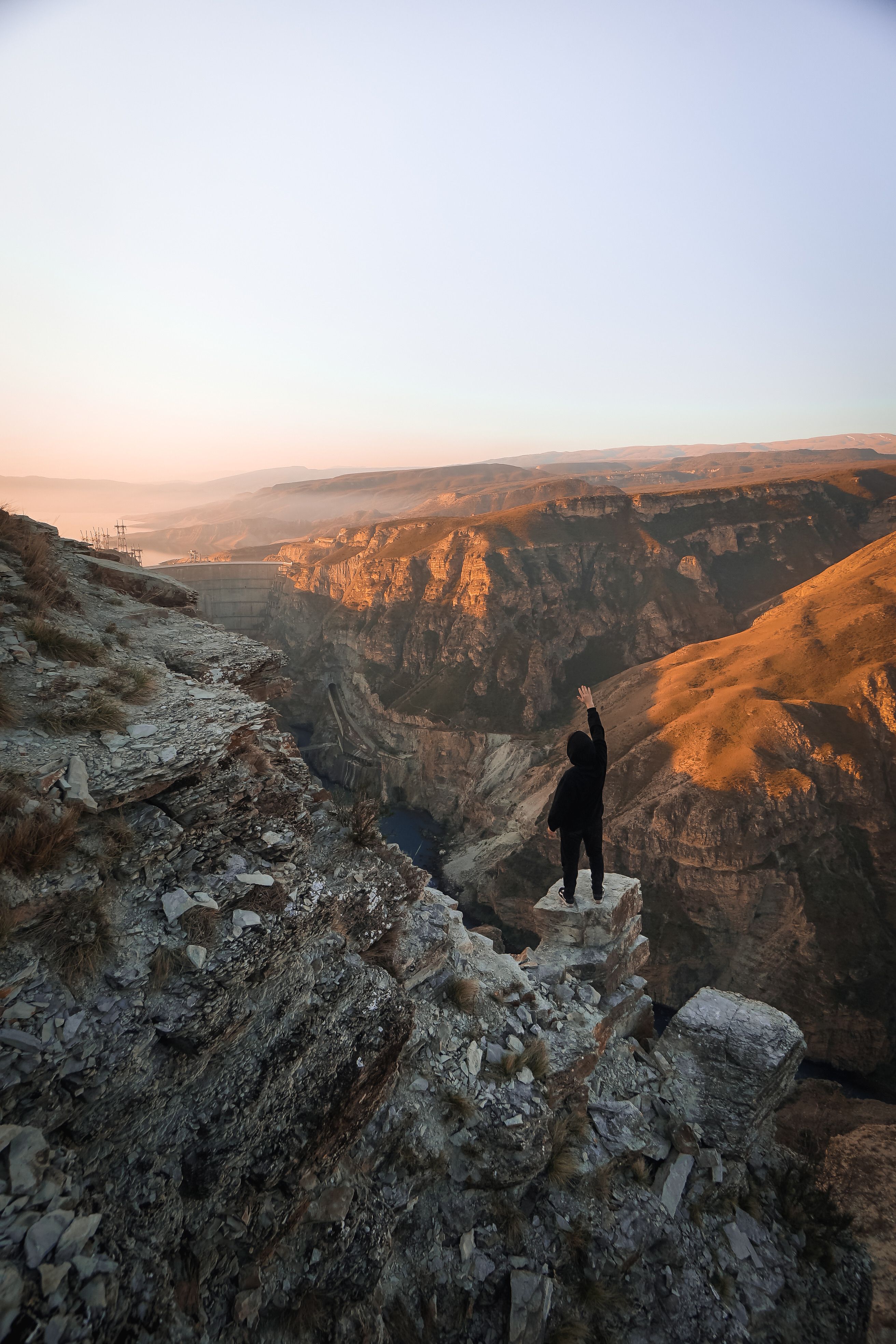 Man Standing on Rocks Edge over Valley at Sunset · Free Stock Photo